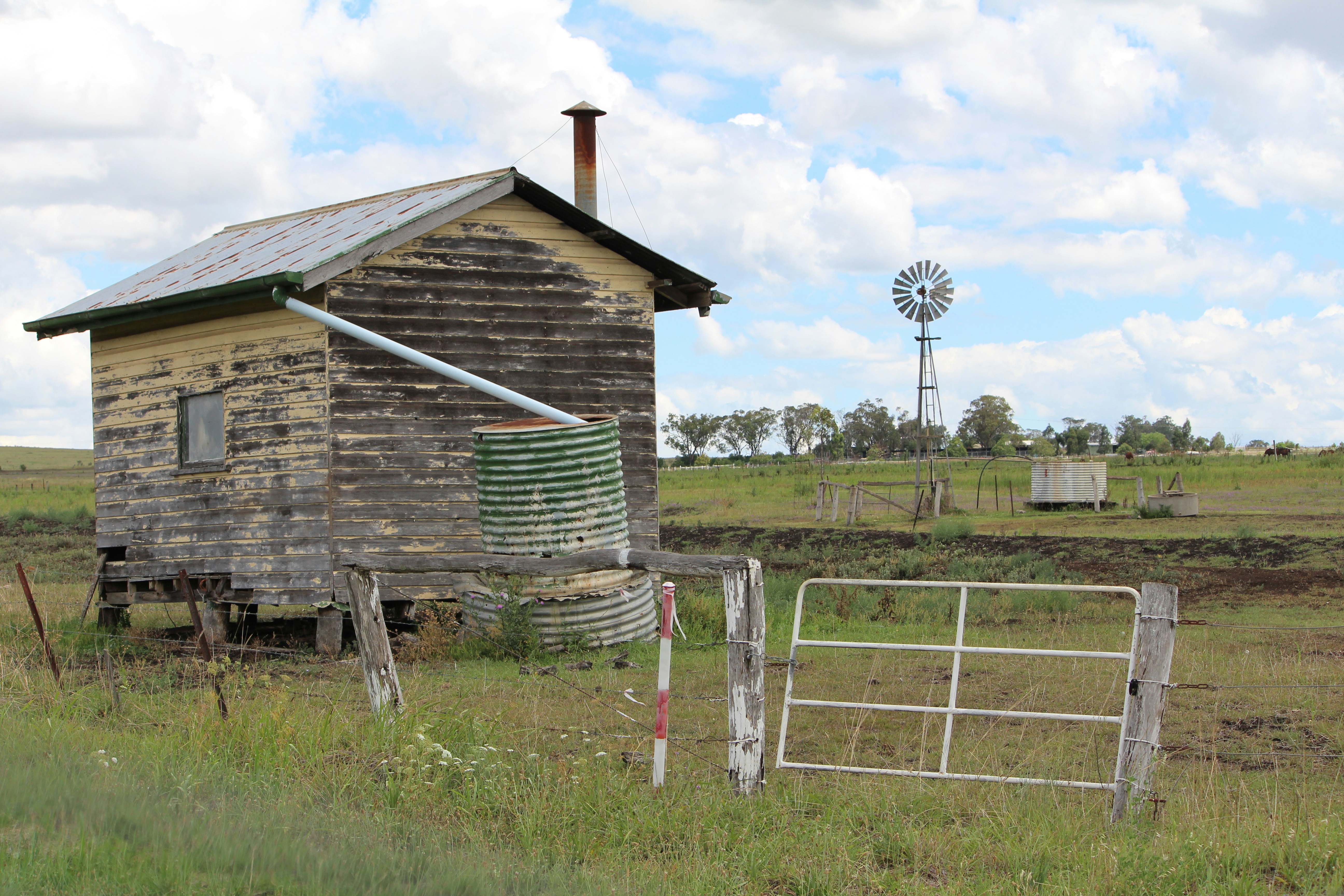 A run down building in a field with a windmill in the background photo ...
