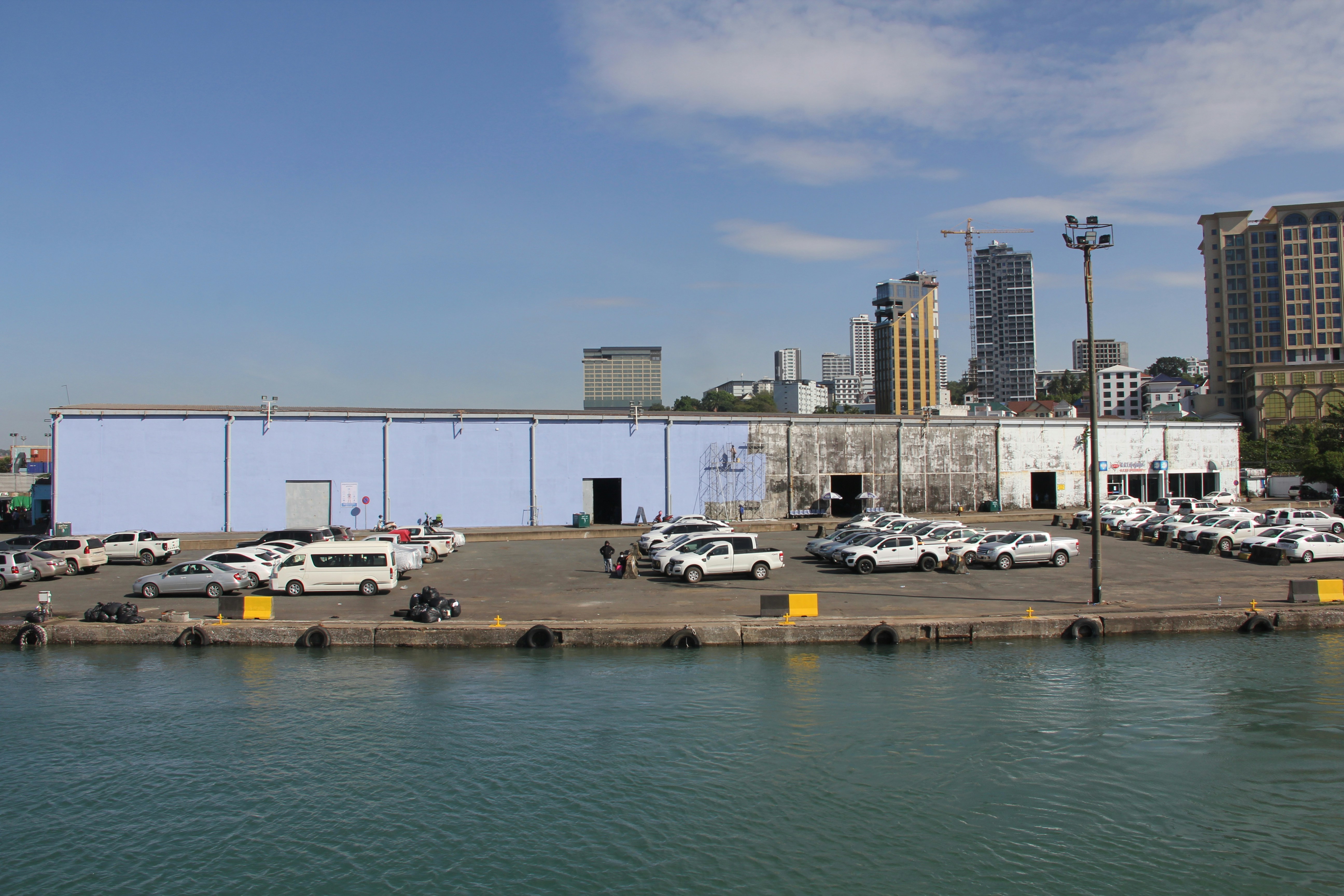 Harborfront Rows: Cars, Cranes, and a Quiet Blue Warehouse