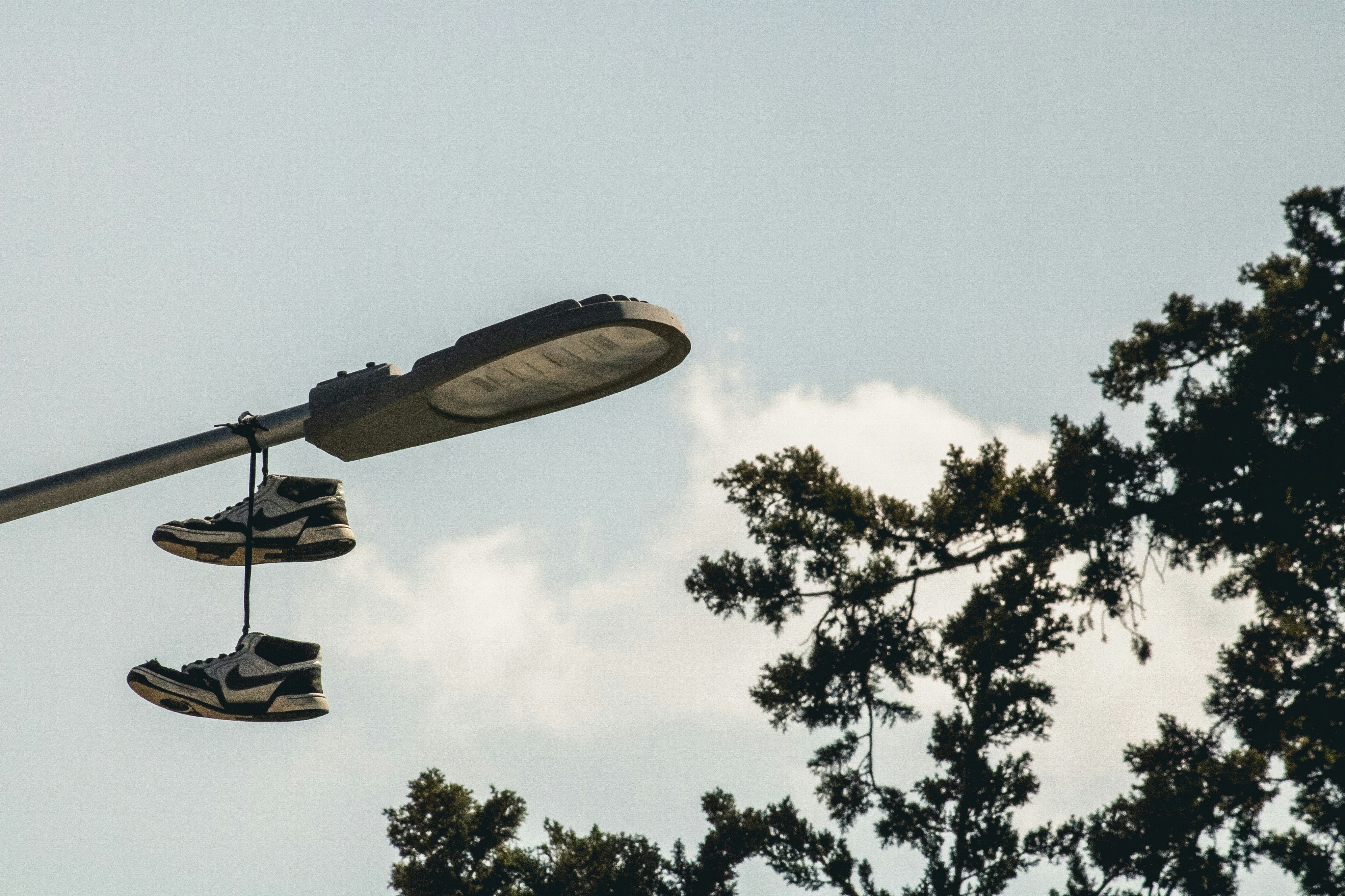 Shoes Dangling from a Streetlamp Against a Calm Sky