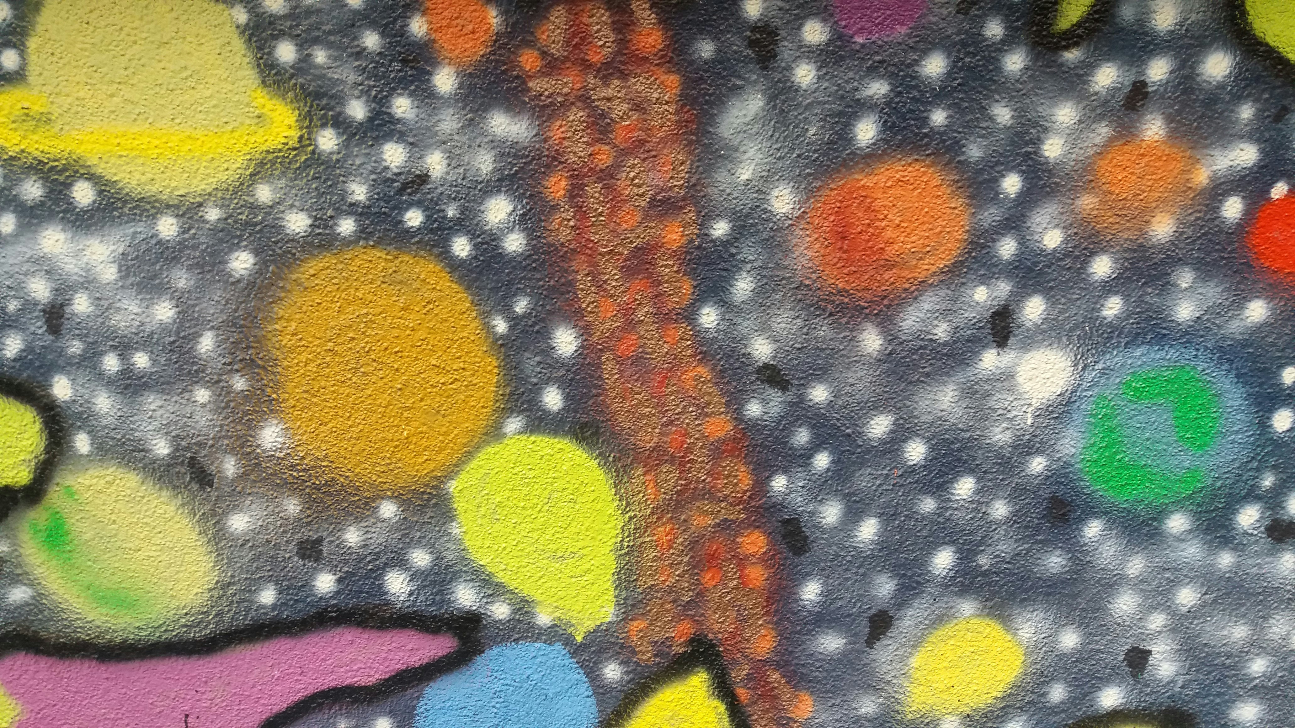 Vibrant mural depicting a cosmic scene with colorful planets and a swirling galaxy. The artwork captures the essence of space exploration.