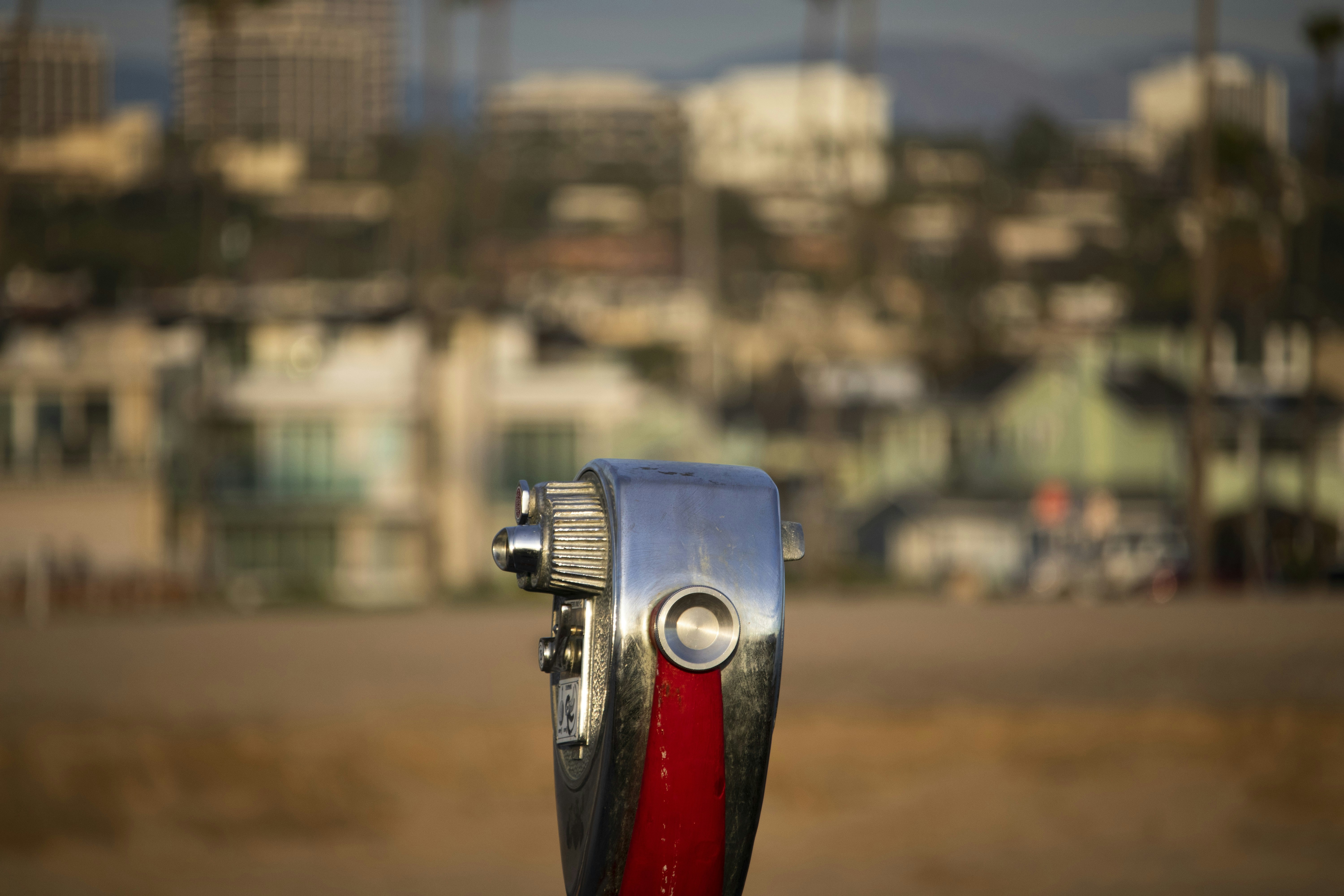 a close up of a parking meter with a city in the background