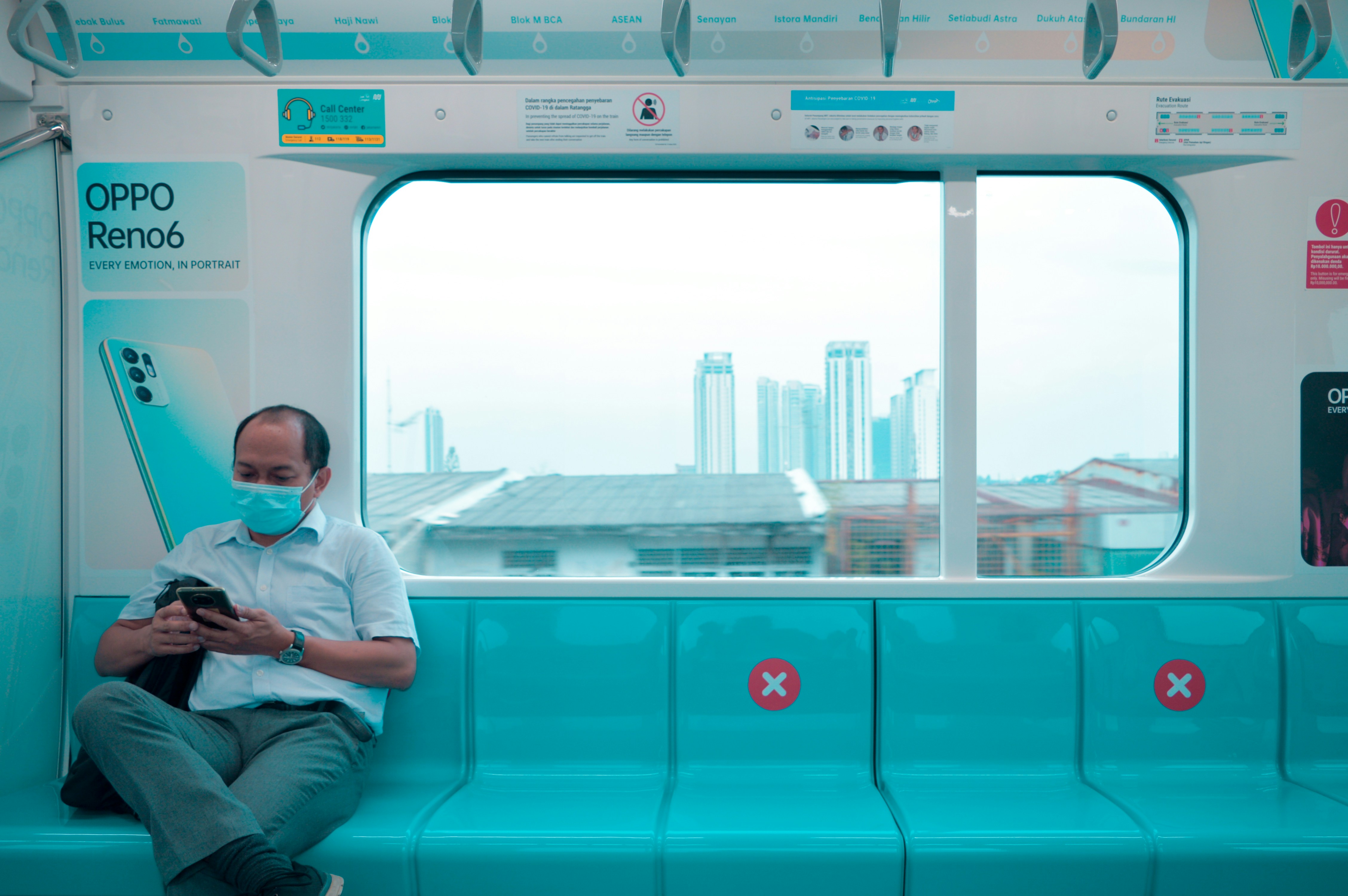a man sitting on a train looking at his cell phone