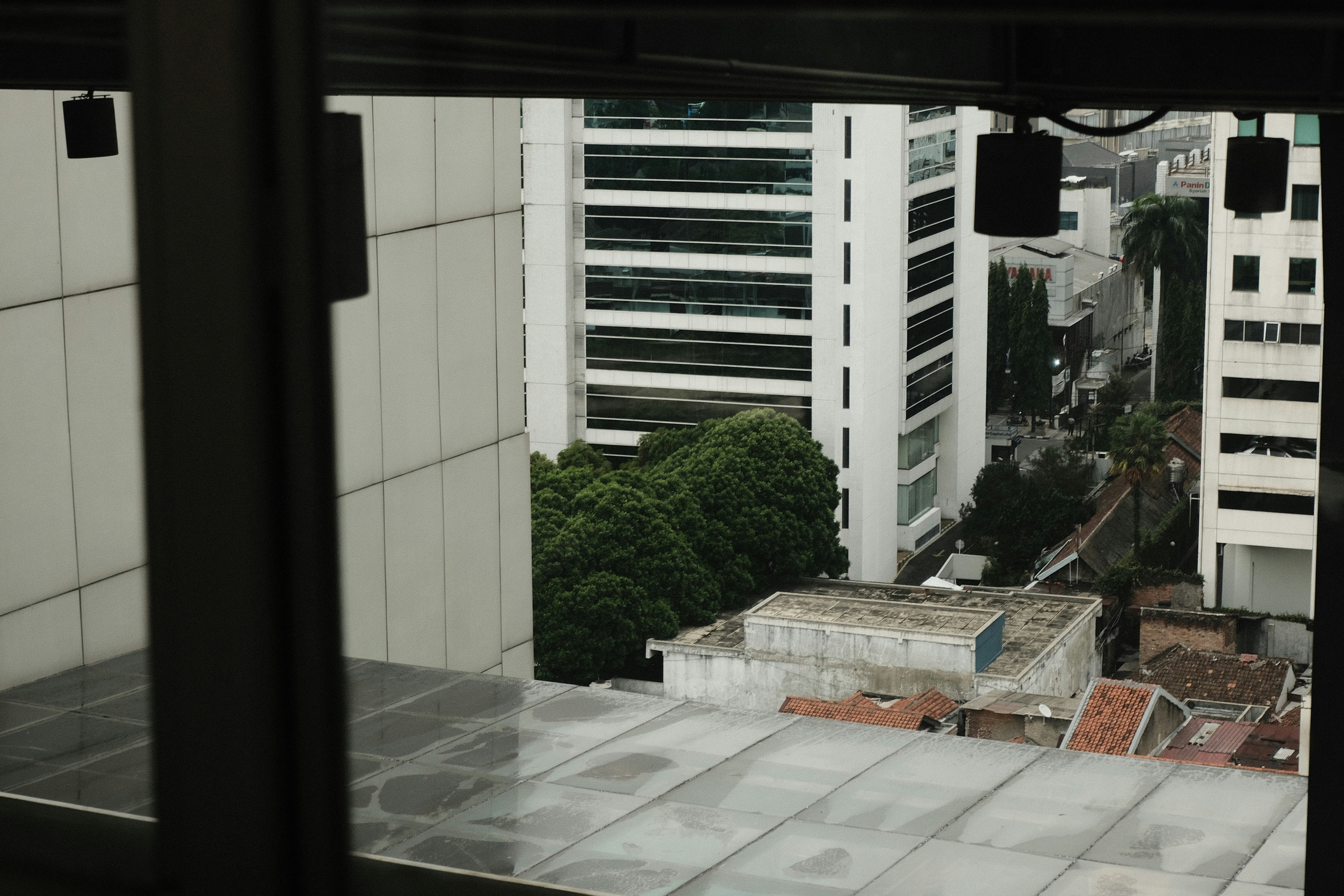 View from a high-rise building capturing urban architecture and greenery. The scene highlights the contrast between modern structures and natural elements.