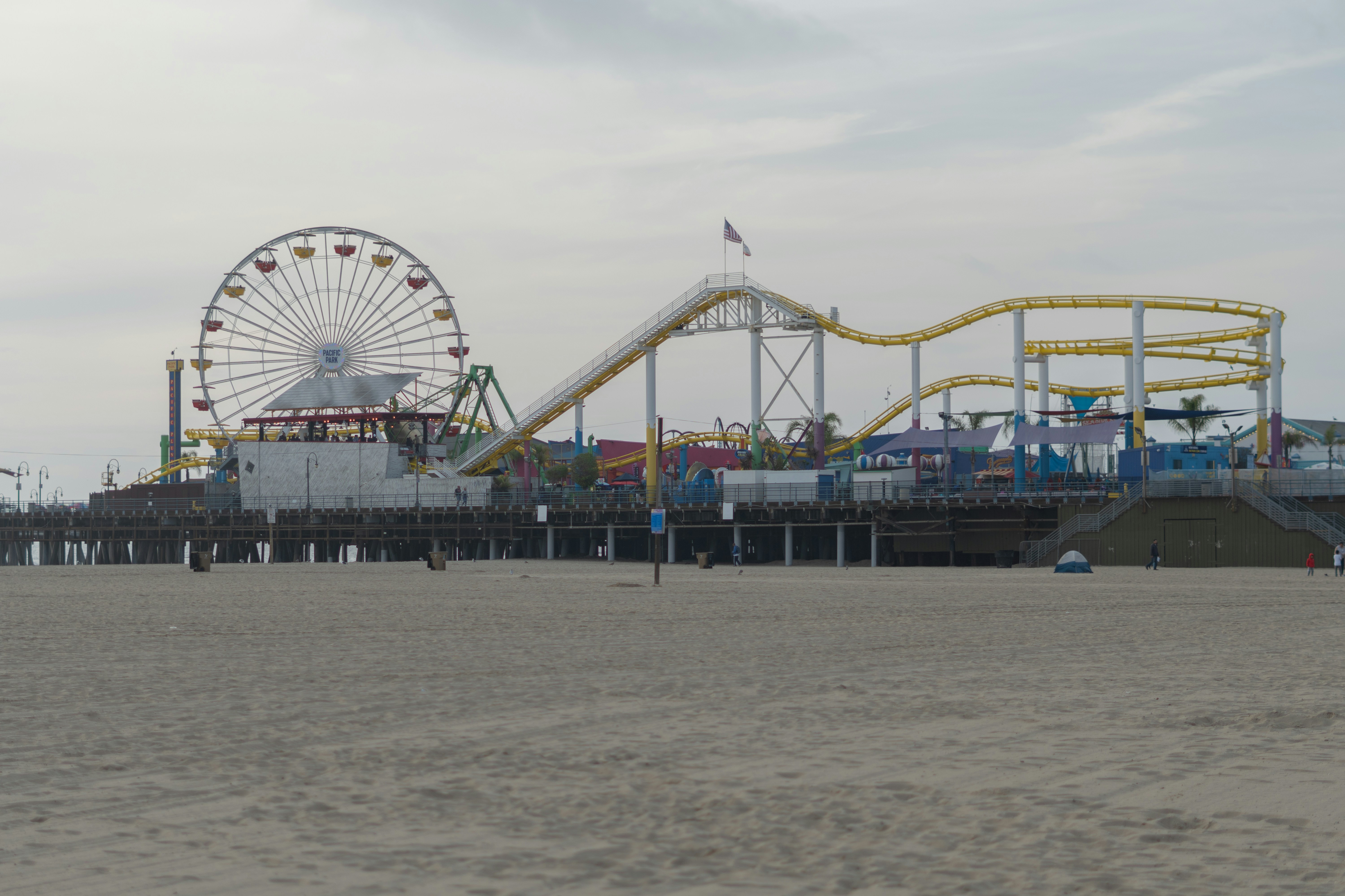 Pierfront Amusement Echoes: Ferris Wheel and Roller Coaster Rising Over a Quiet Beach