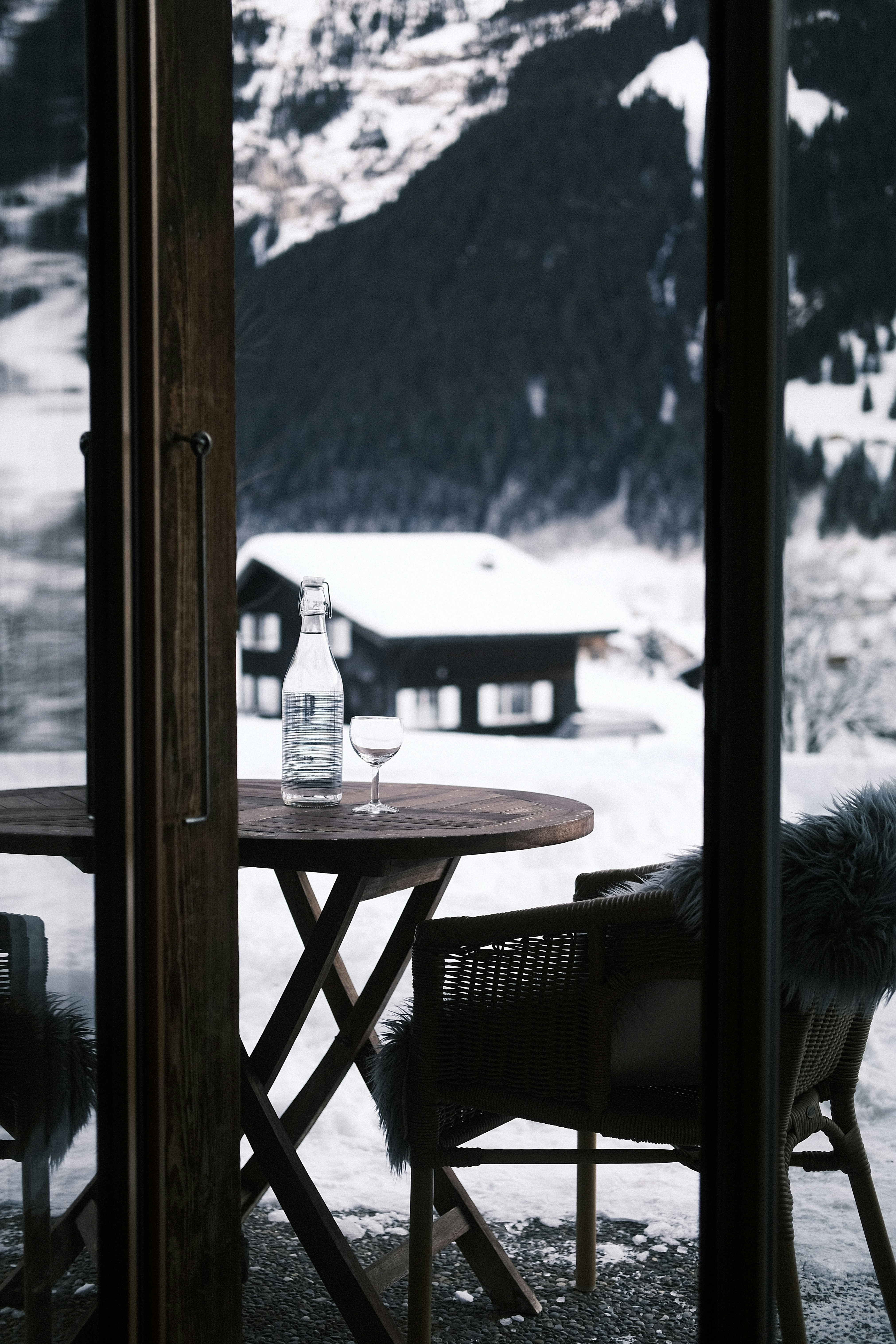 Alpine Balcony Quiet: Bottle and Glass Amid Snow-Laced Light