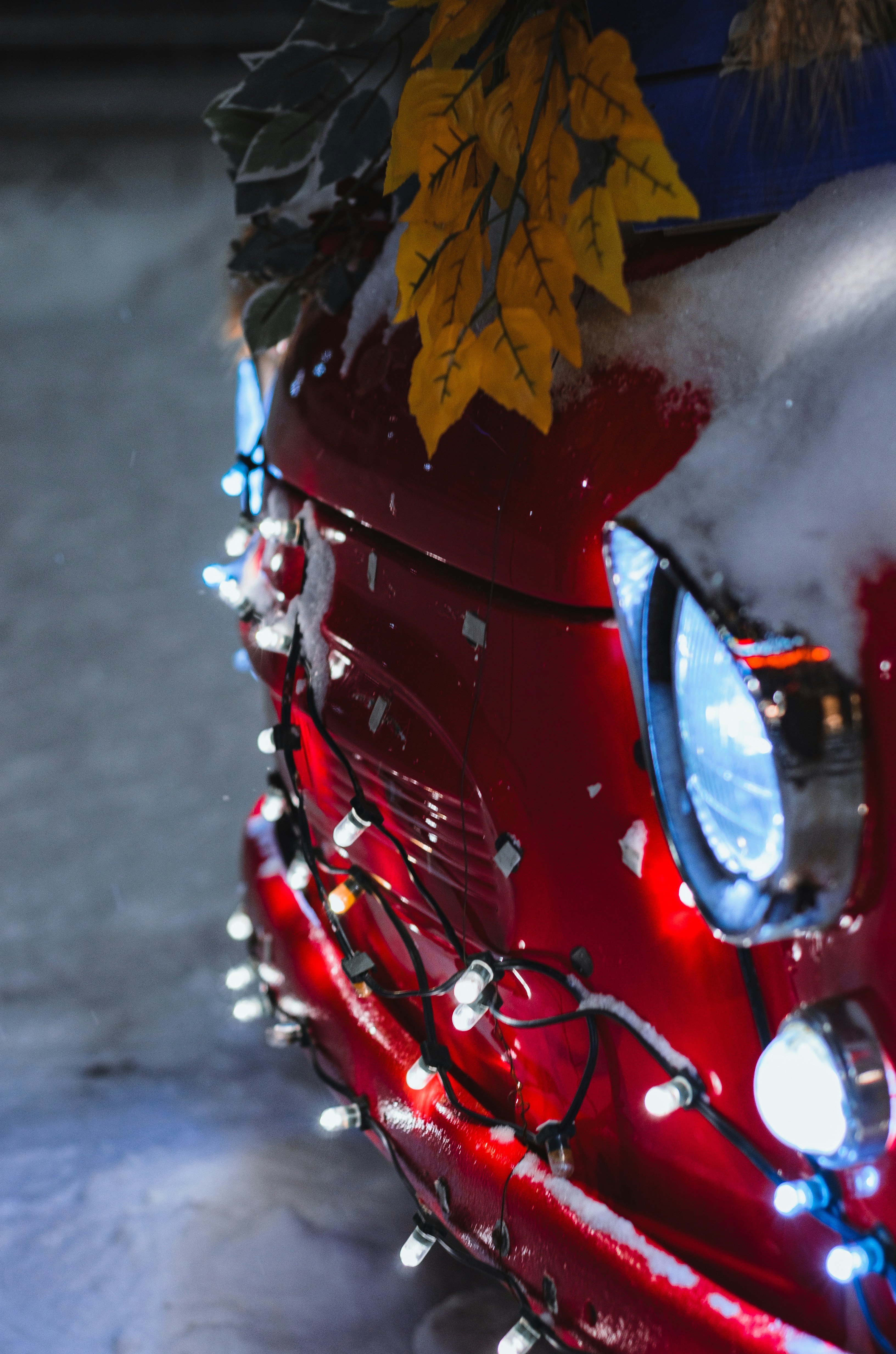 Fairy-Lit Frost: Red Vintage Car Adorned with Snow and Autumn Leaves
