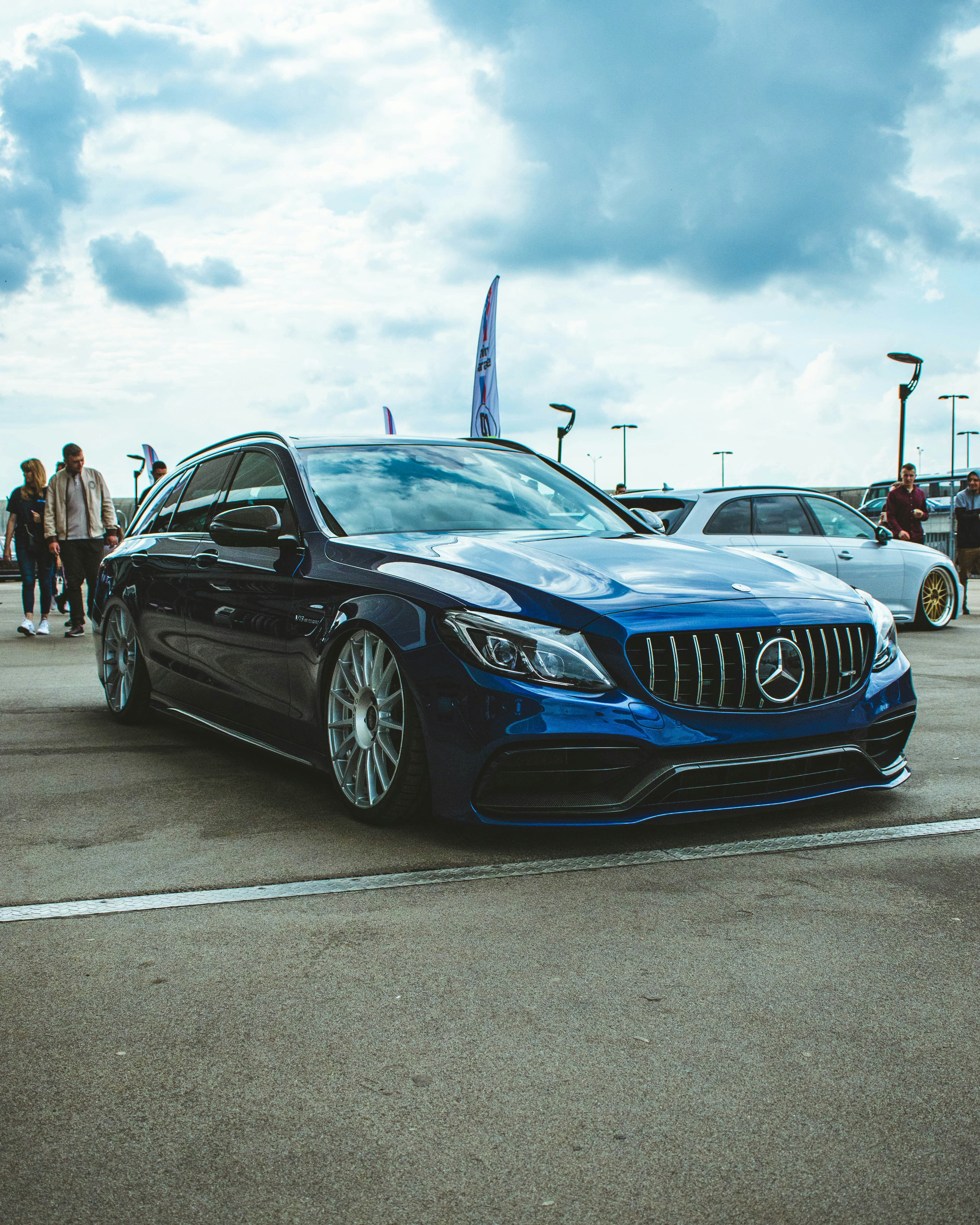Blue Mercedes-Benz with aggressive stance commands attention at a crowded car meet