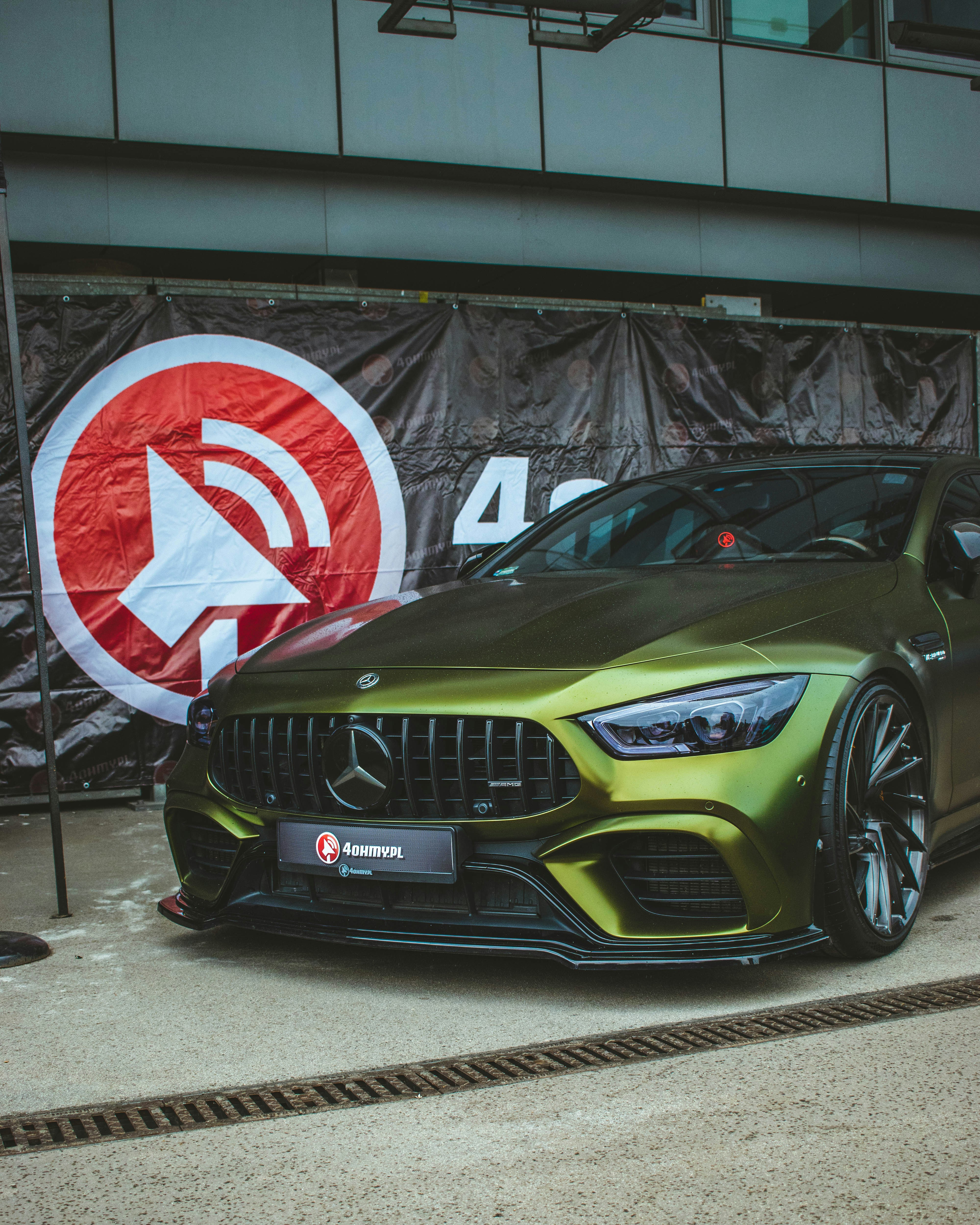 Un Mercedes AMG coupé verde estacionado frente a un cartel foto ...