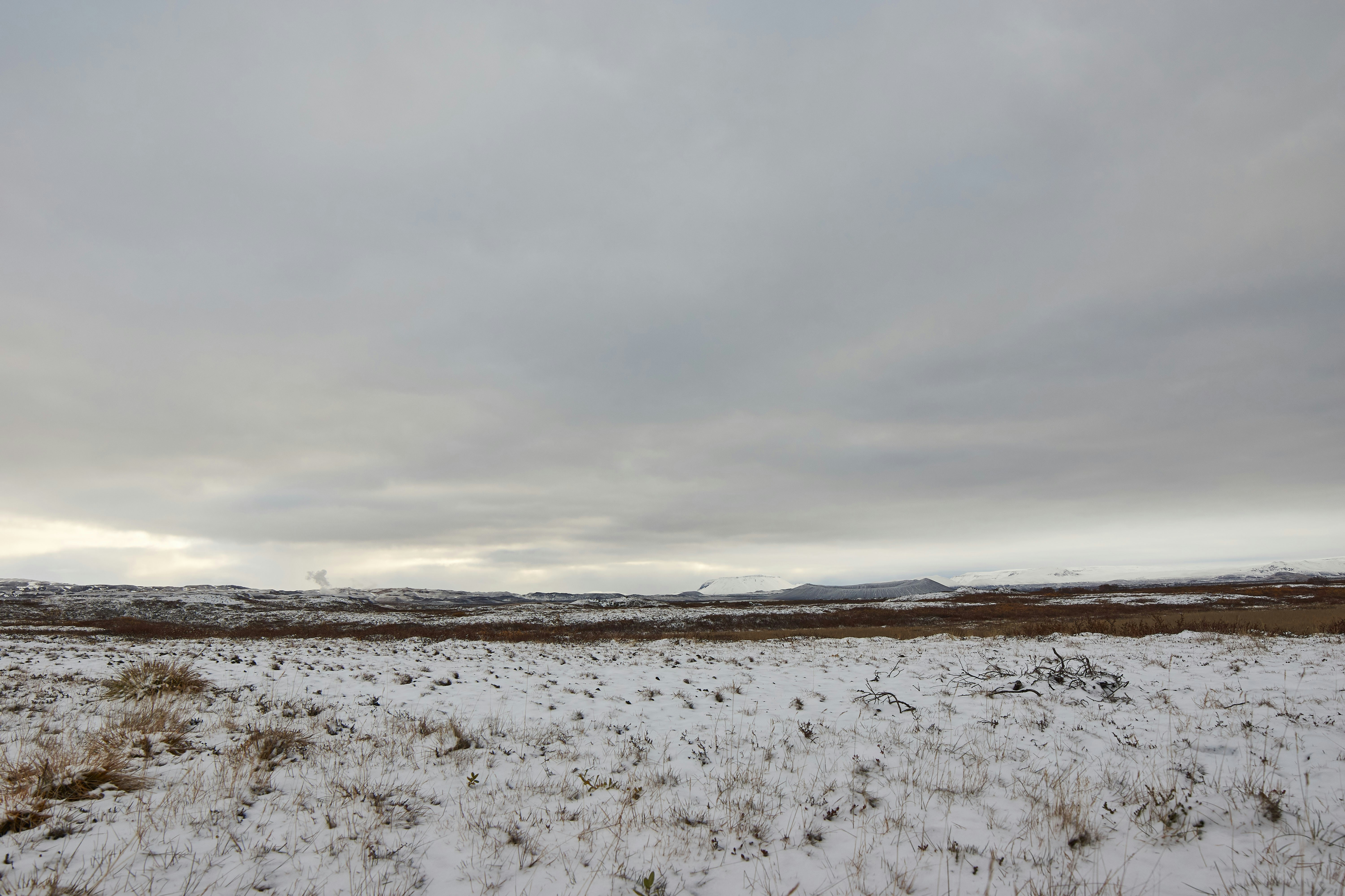 A snow covered field with mountains in the distance photo – Free Grey ...
