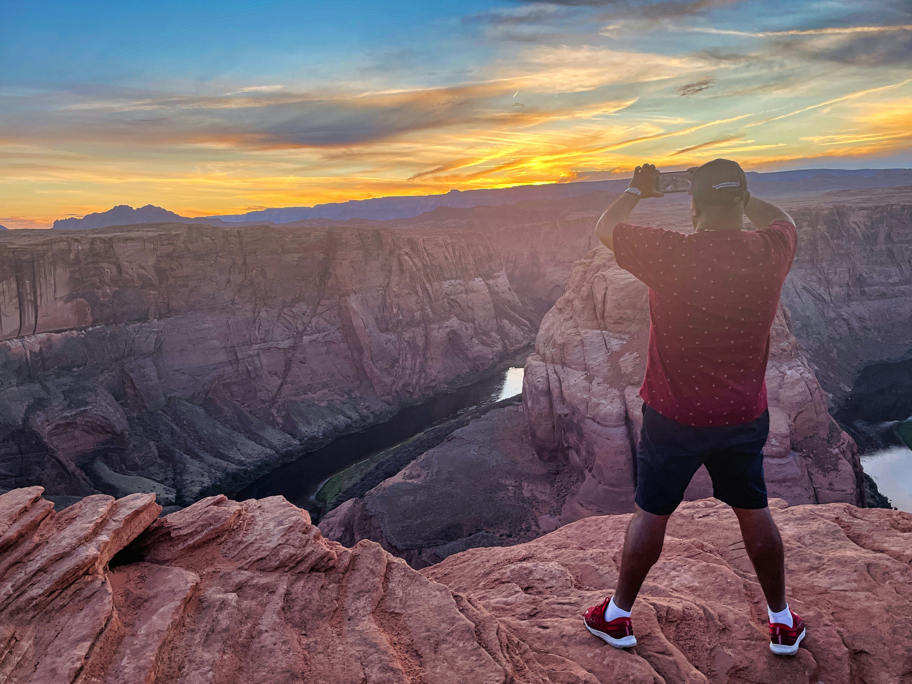 a man taking a picture of the sunset over a canyon
