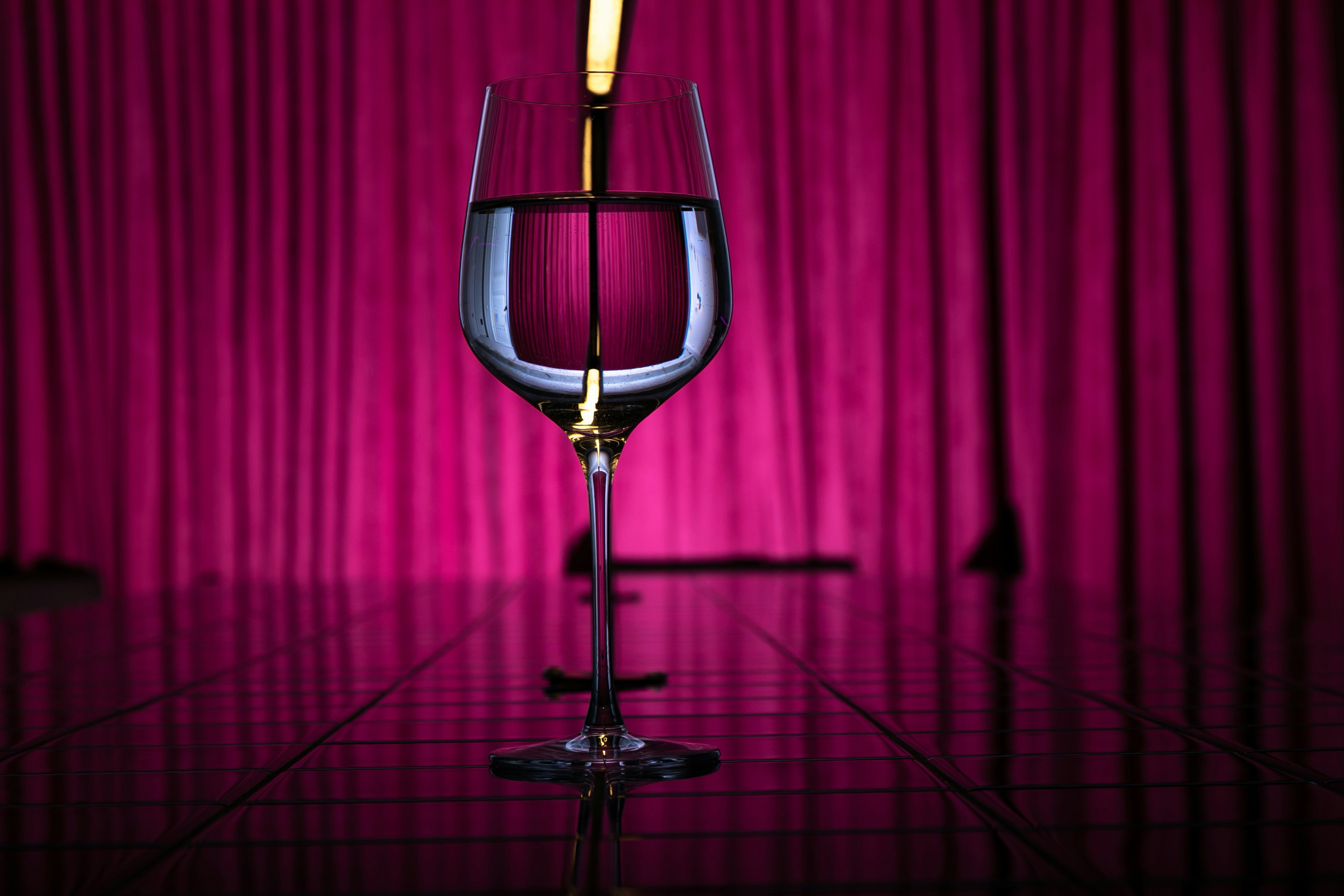 Lone Wine Glass Under Violet Spotlight on a Reflective Table