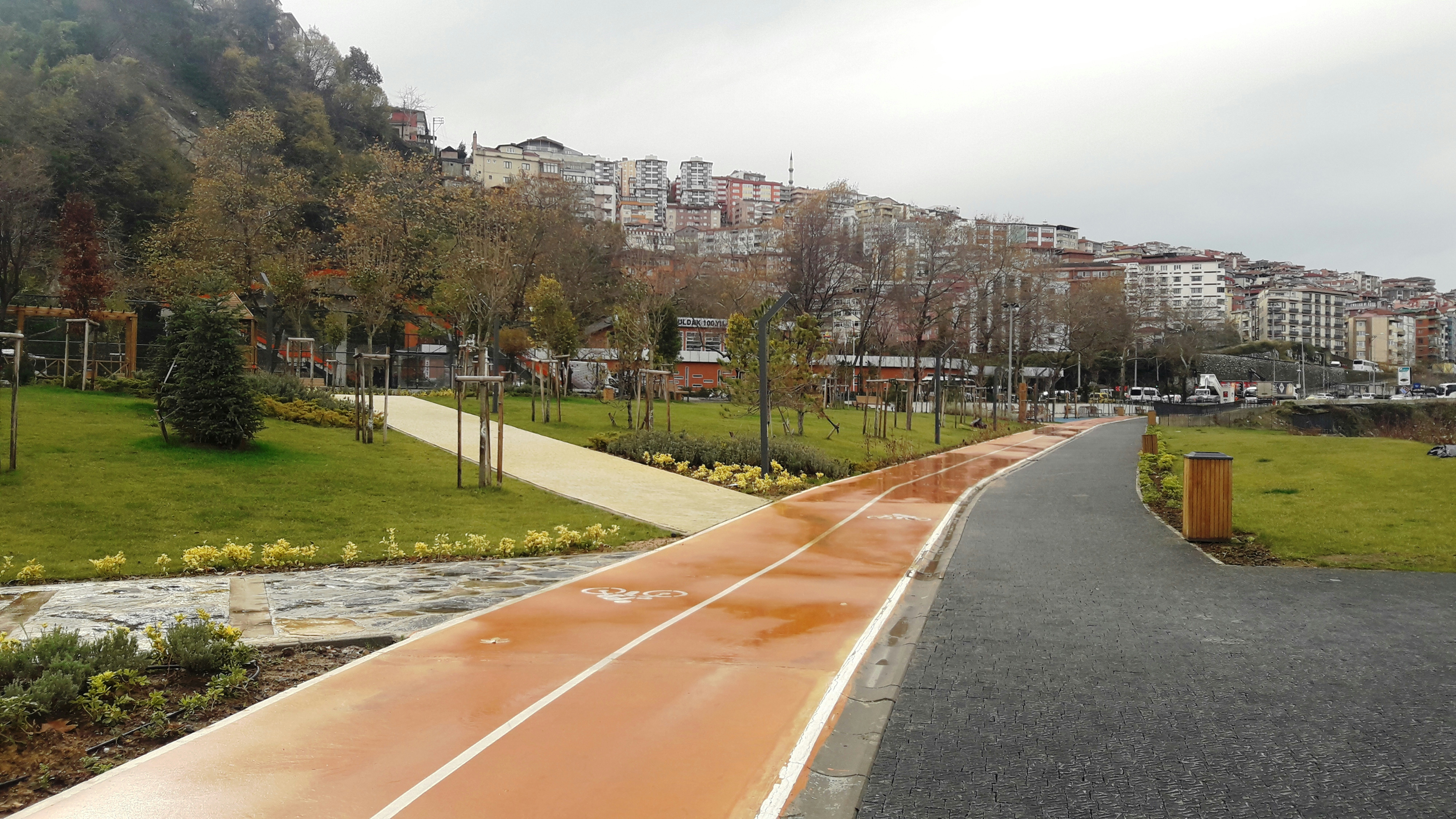 Park pathways with a cityscape backdrop under a cloudy sky.