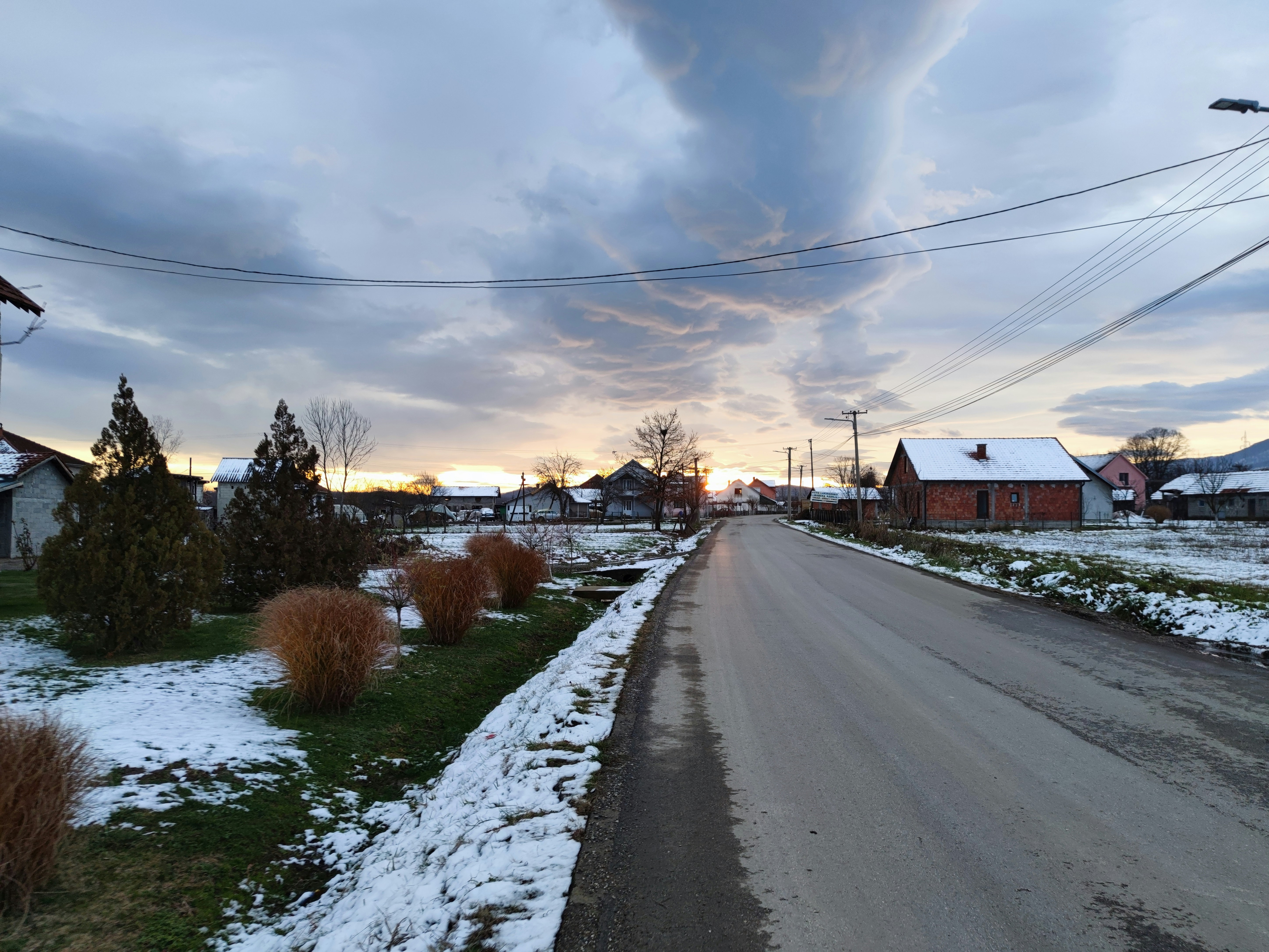a street with snow on the ground and houses in the background