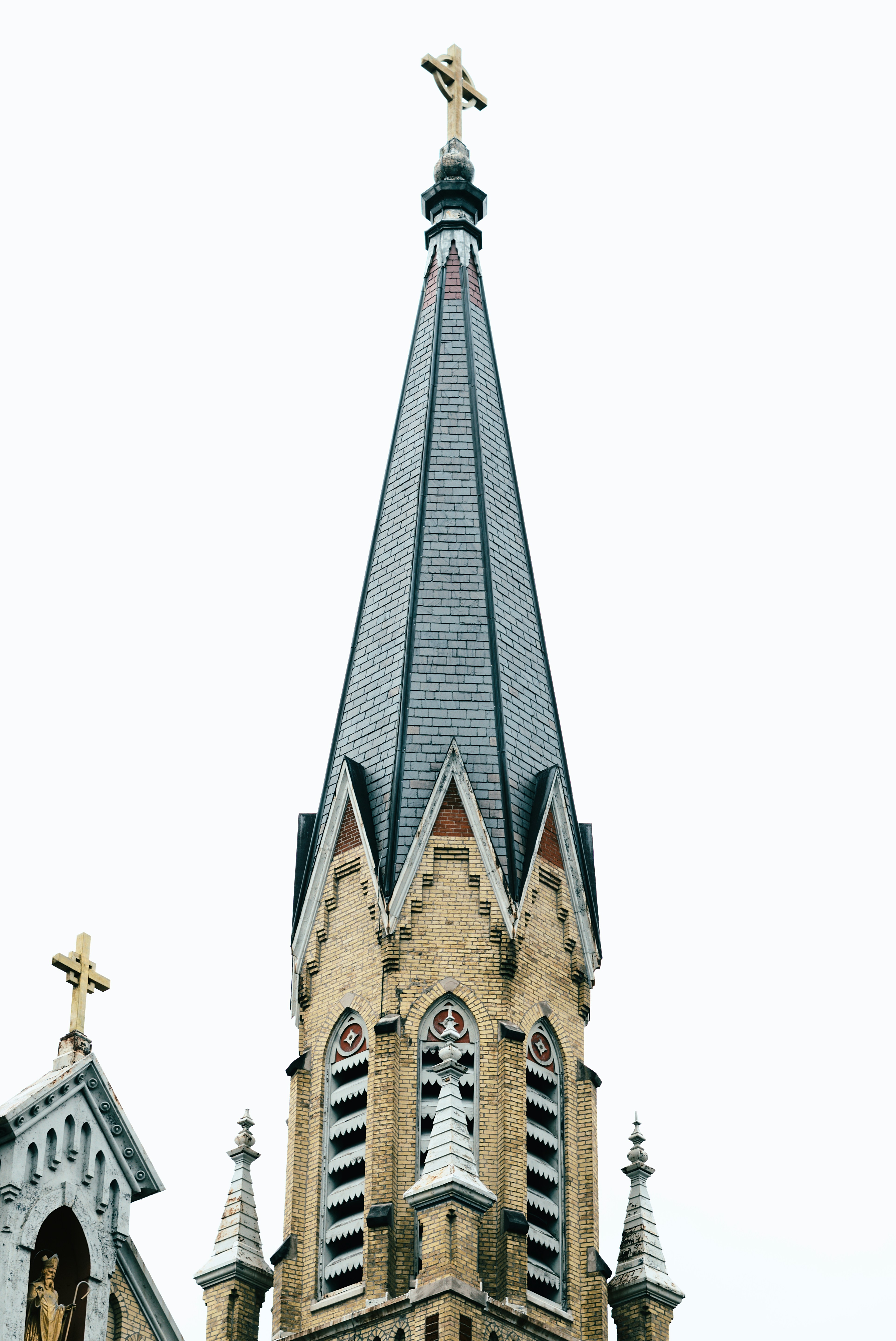 Gothic church spire reaching skyward, adorned with intricate architectural details and a prominent cross at the pinnacle.
