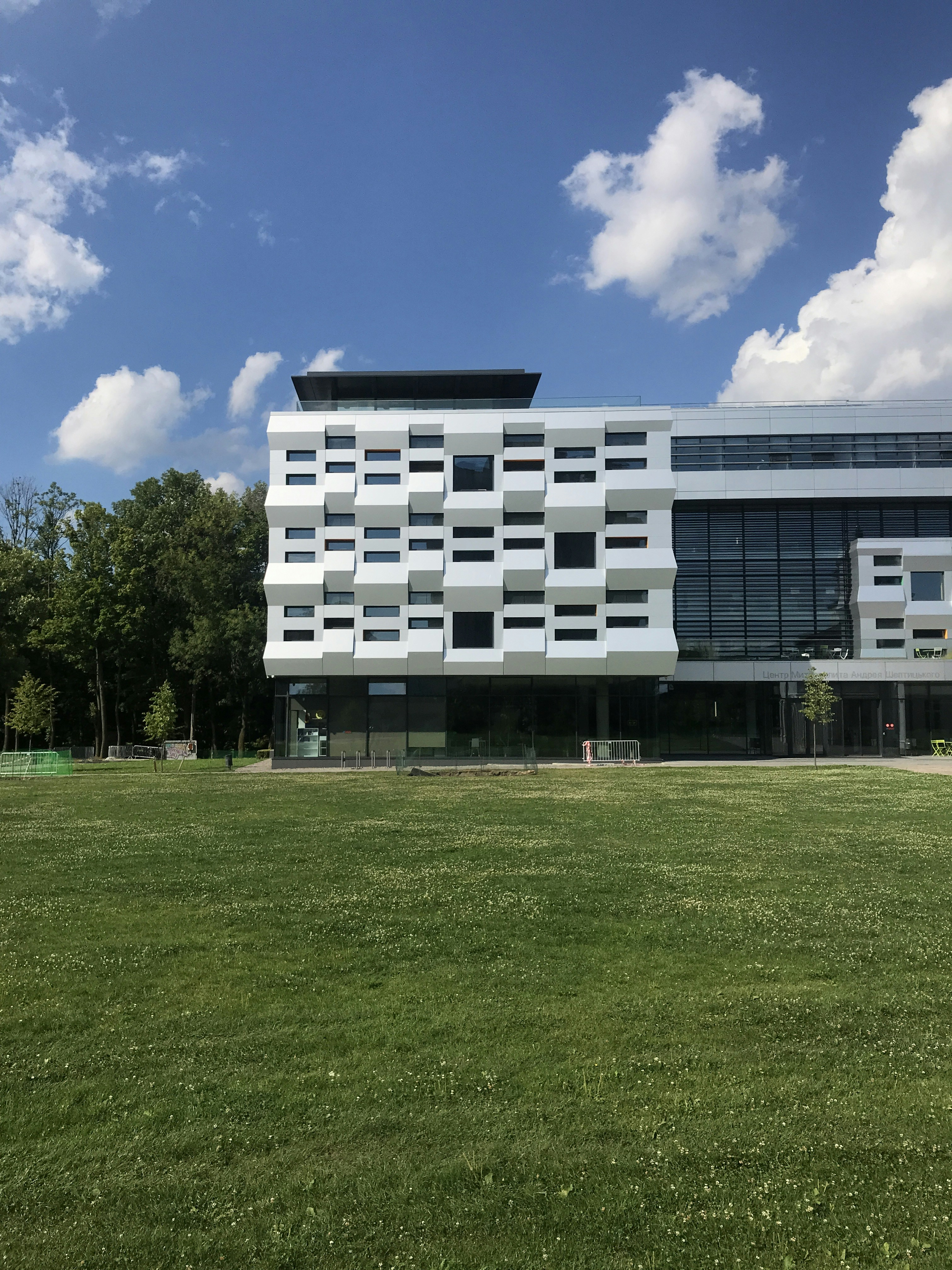 Geometric Modernity: Faceted White Facade Amid Green Field