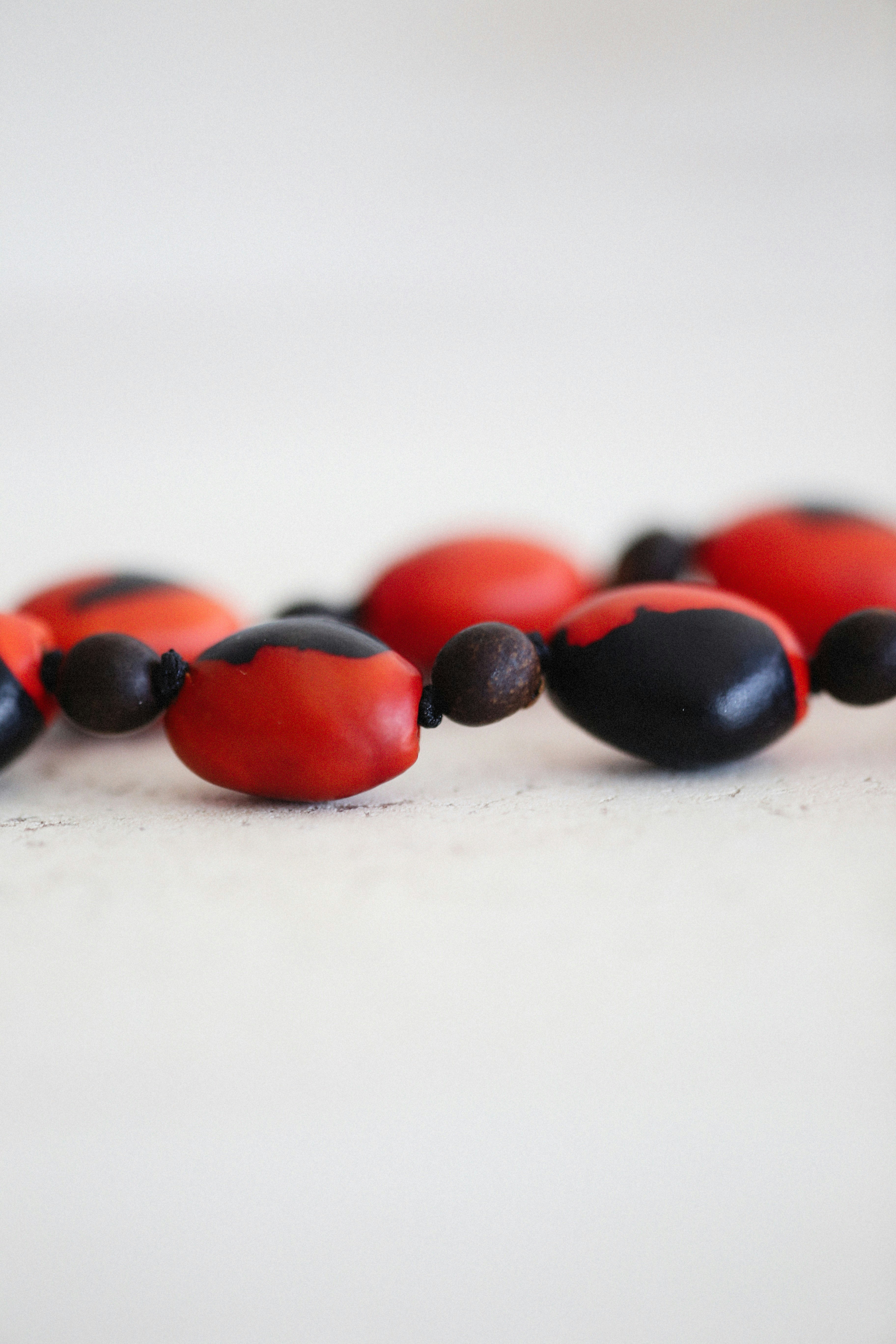 A group of red and black beads laying on top of each other photo – Free ...