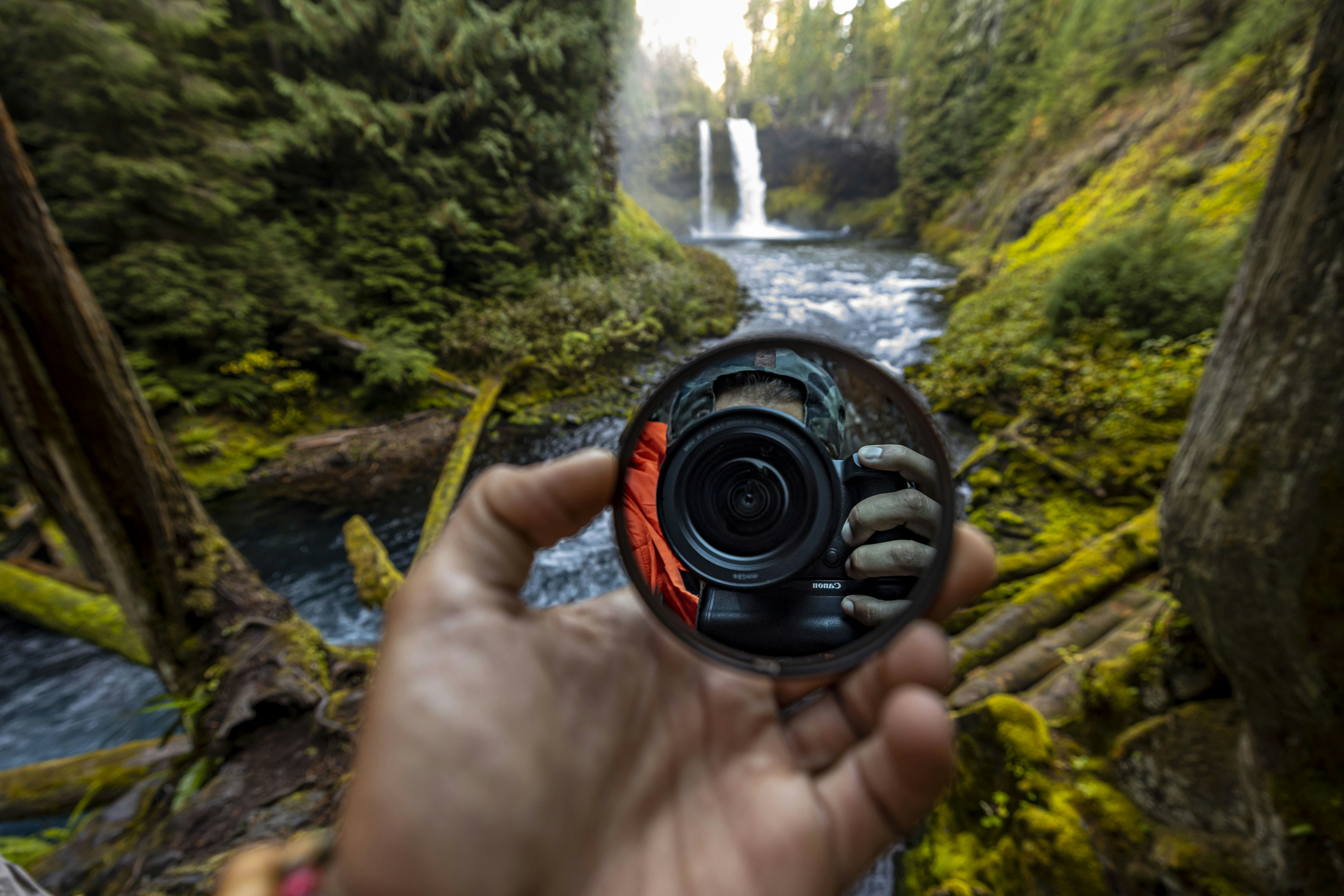 Une personne tenant une caméra devant une cascade photo – Photo Voyage ...