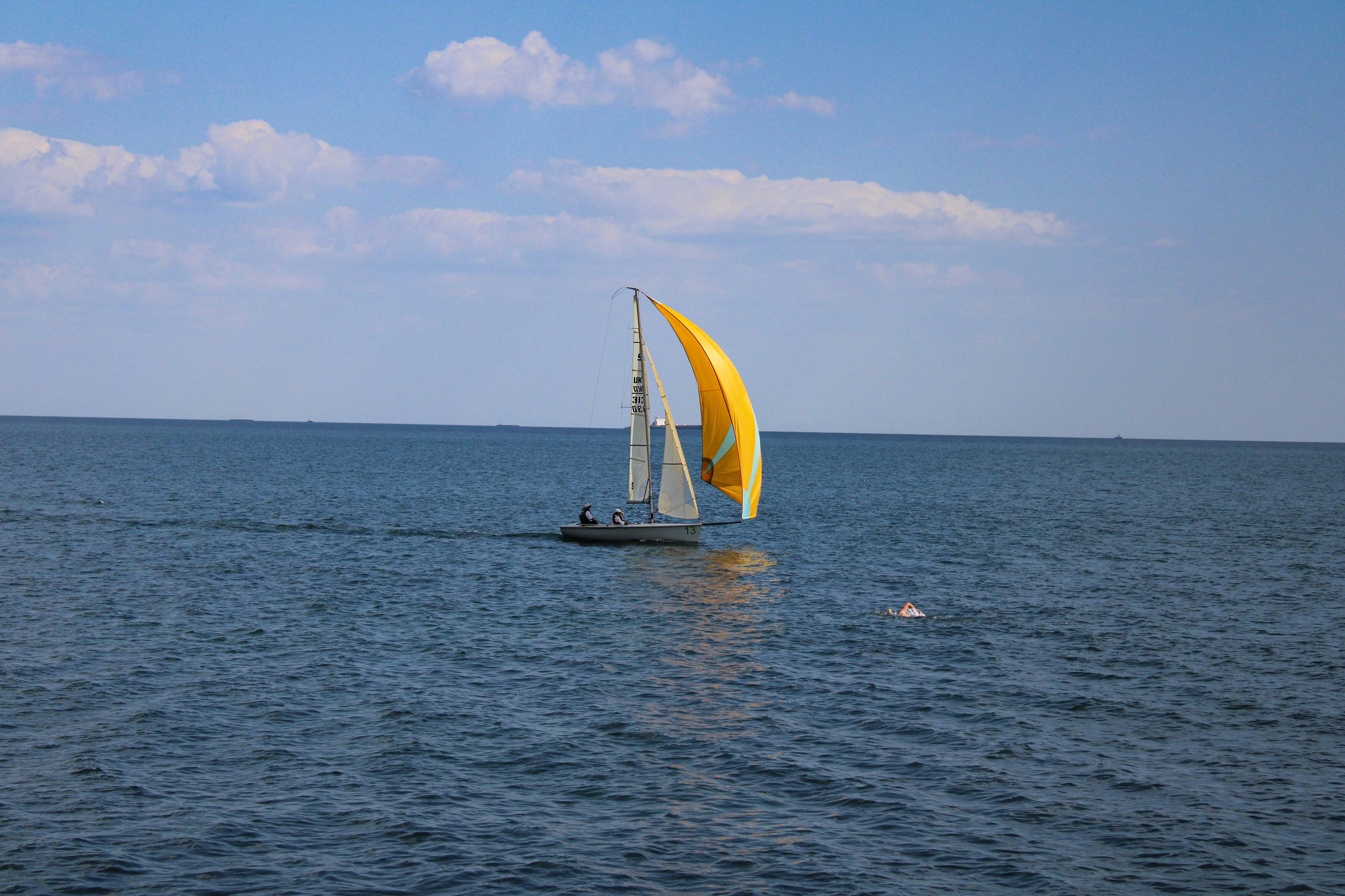 A sailboat with a yellow sail in the middle of the ocean photo – Free ...