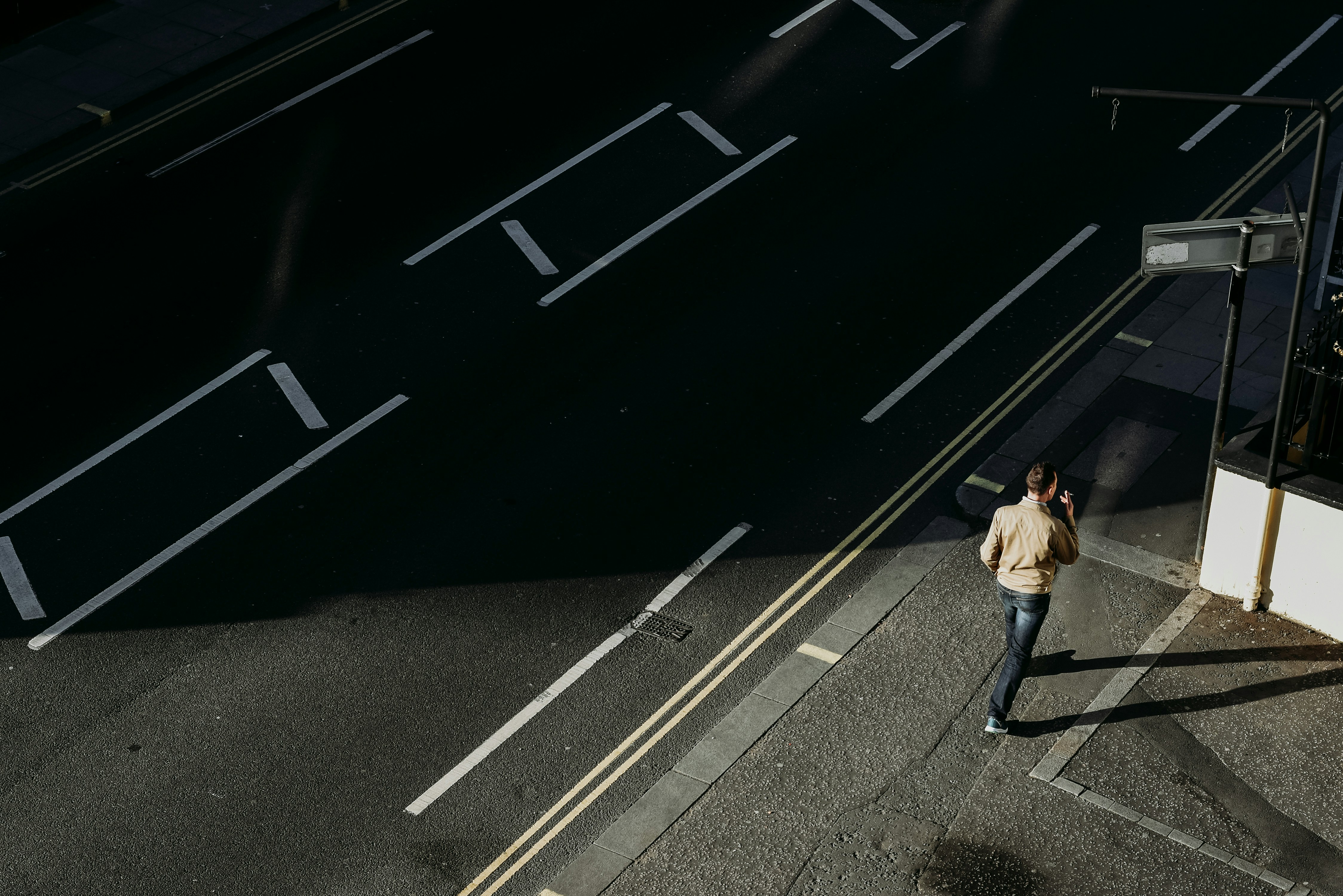 A man walking down a street next to a traffic light photo – Free ...