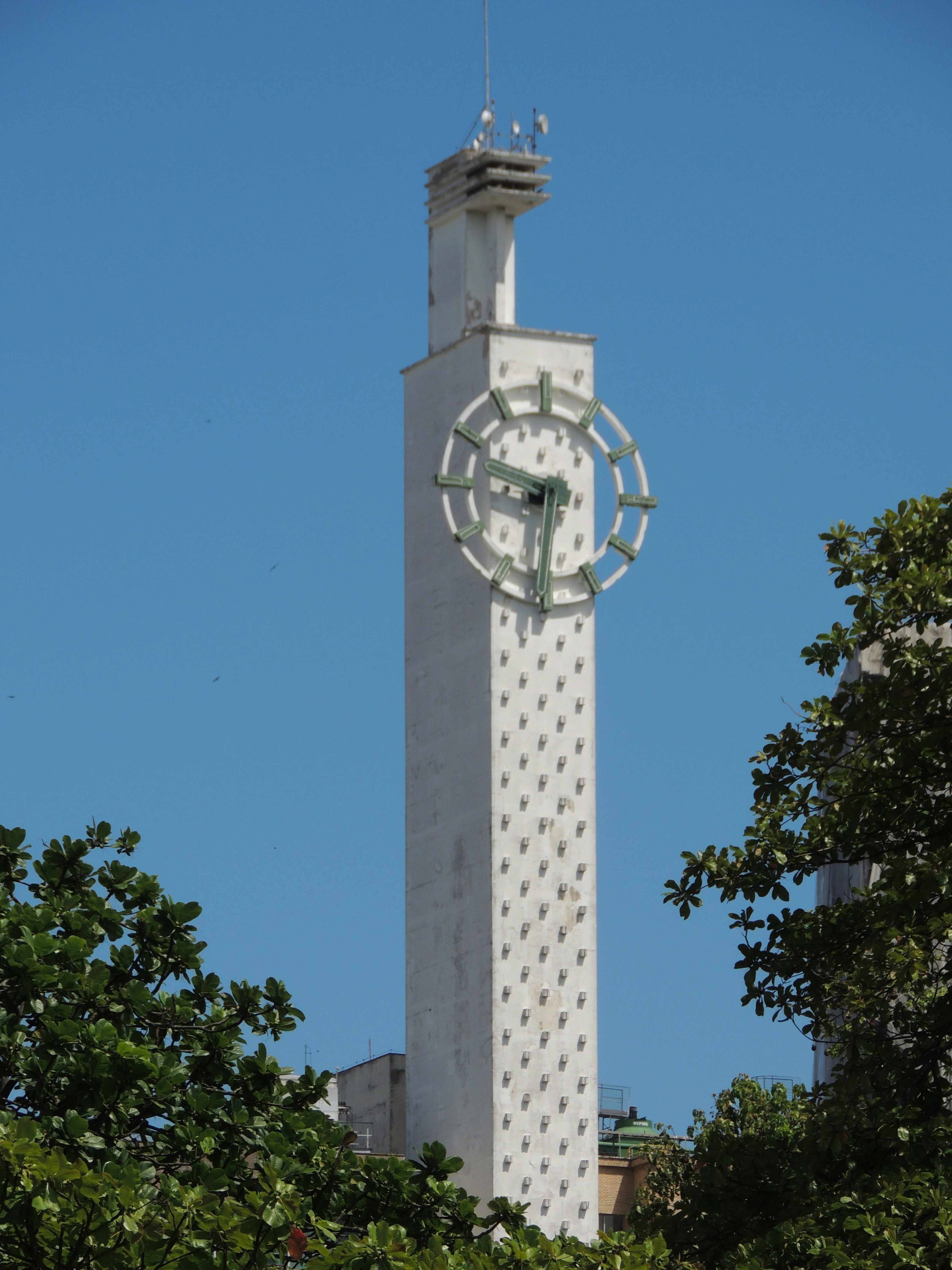 Azure Summit: The White Clock Tower Rising Above a Lush Green Frame
