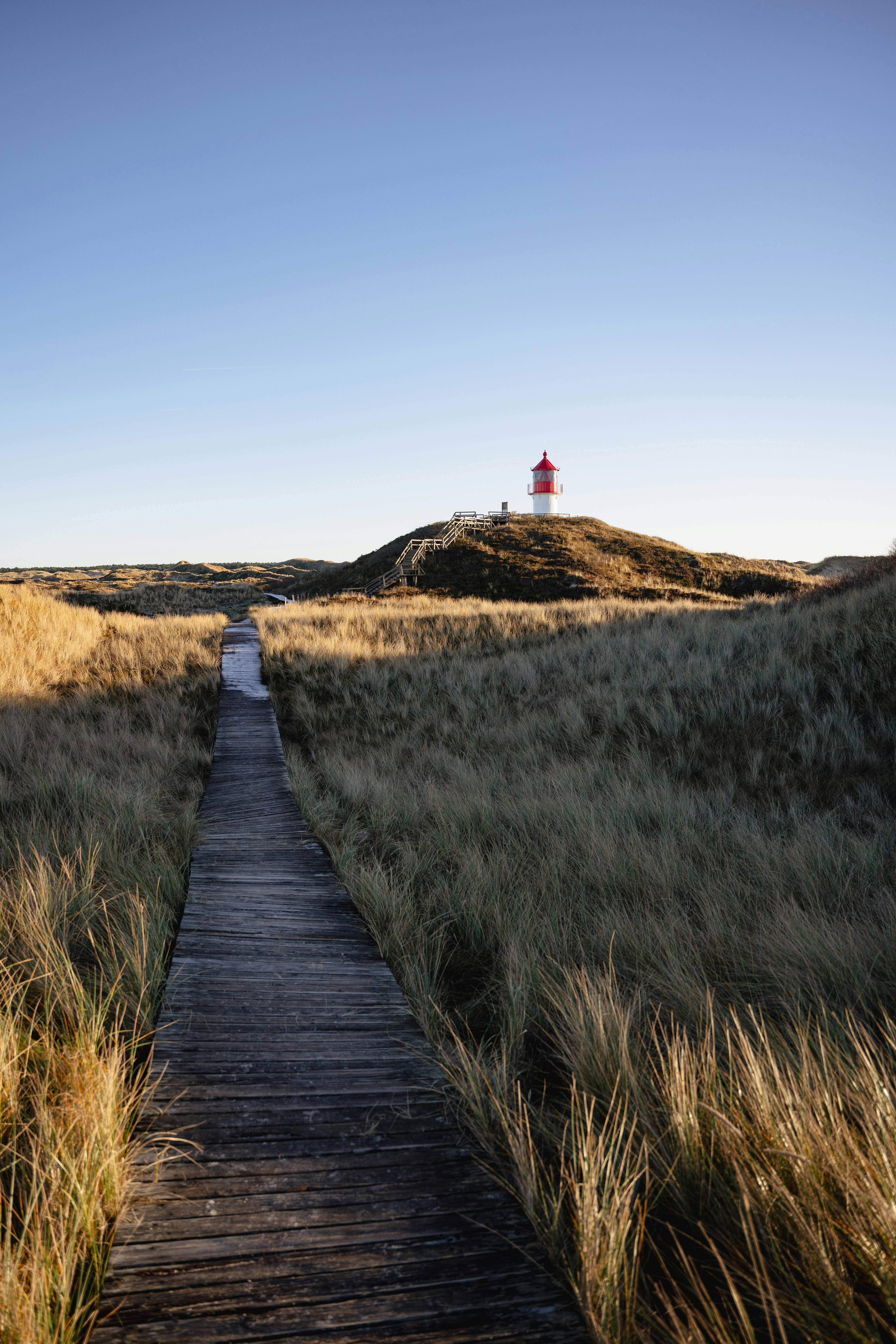 A wooden path leading to a lighthouse on a hill photo – Free Amrum ...