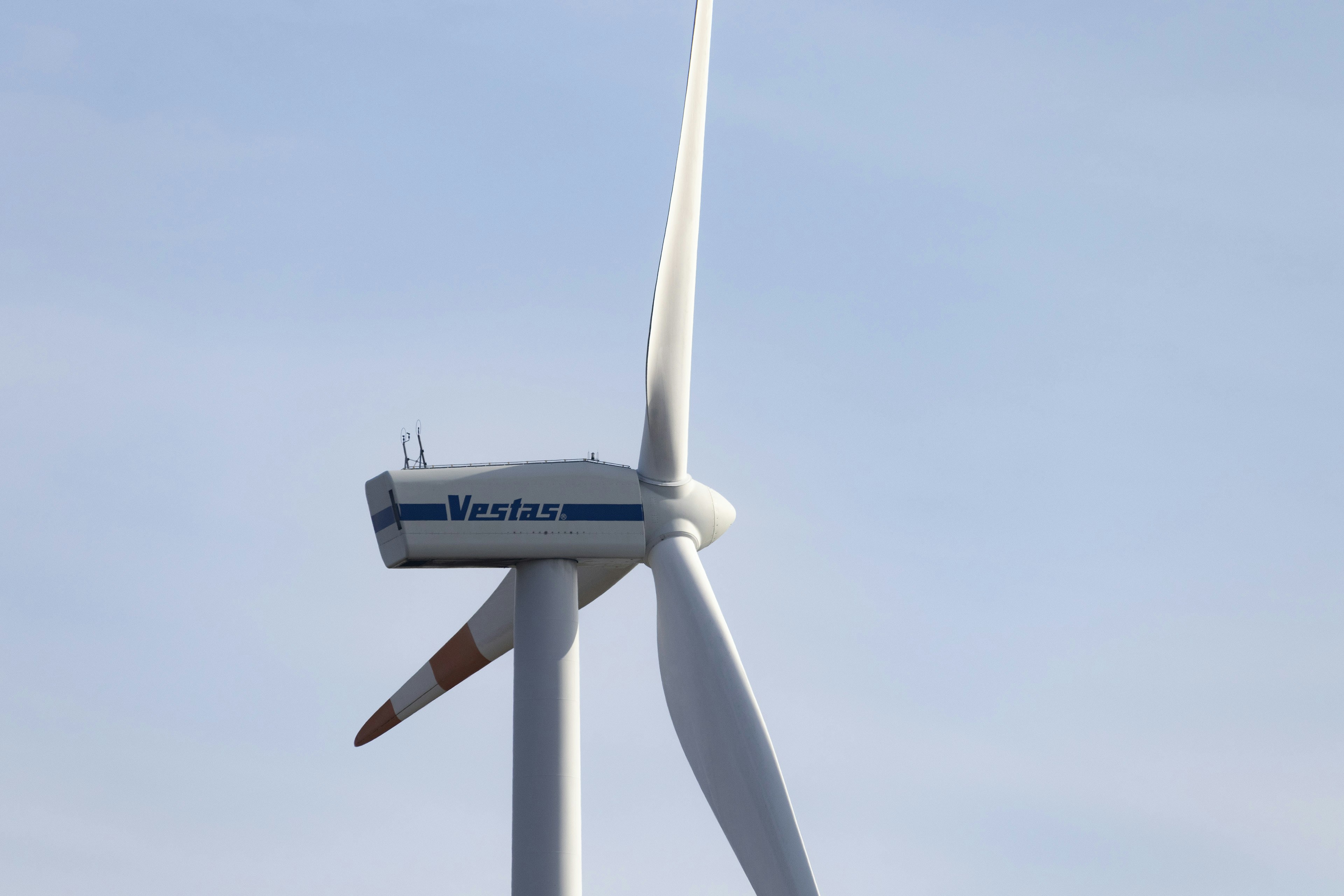 Wind turbine with Vestas branding, showcasing its sleek design against a clear sky. The image emphasizes renewable energy technology.