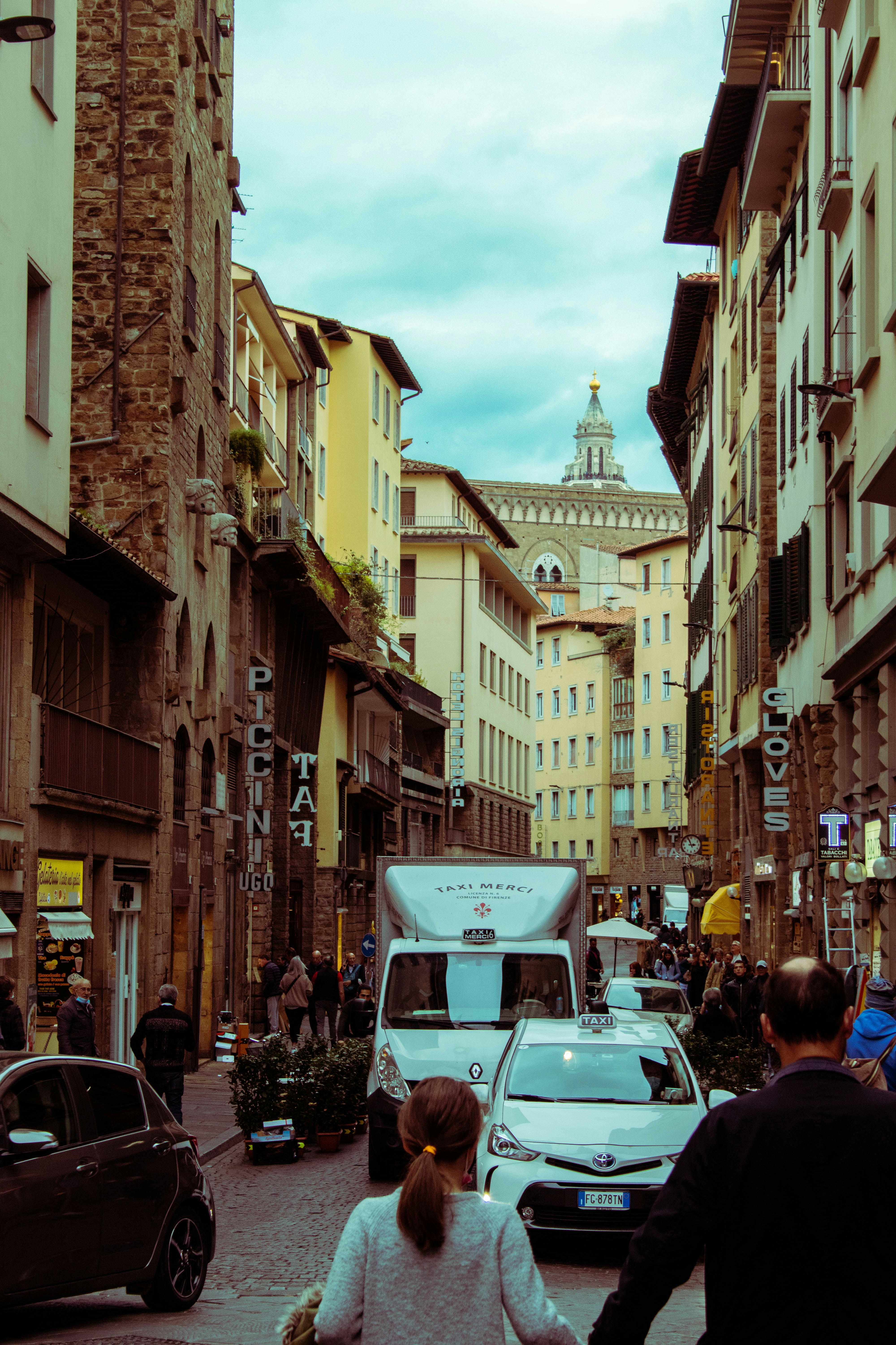 Cobbled European Street: White Delivery Truck Navigates a Lively Historic Corridor
