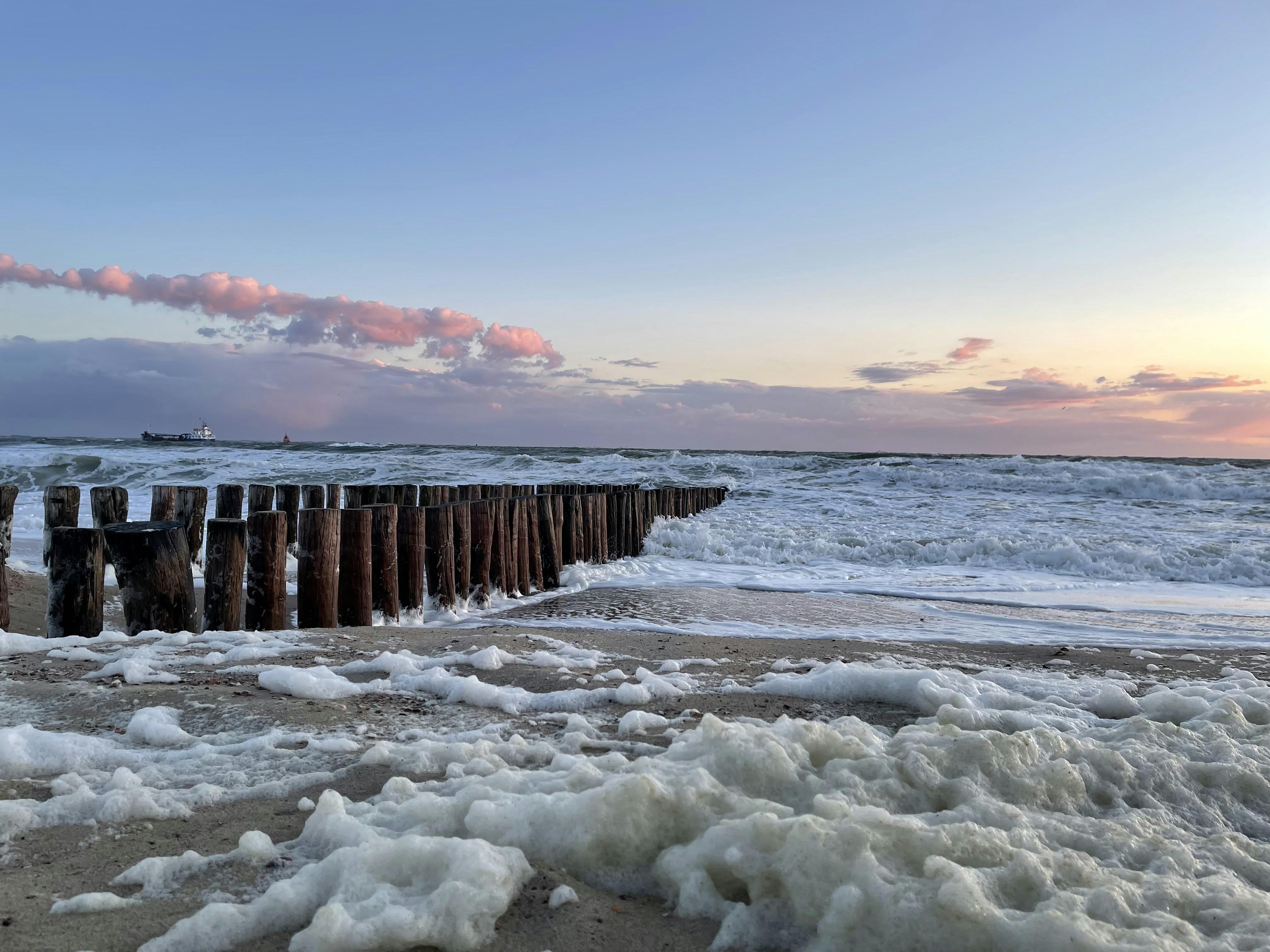 foam from the sea water on the beach during pink sunset
