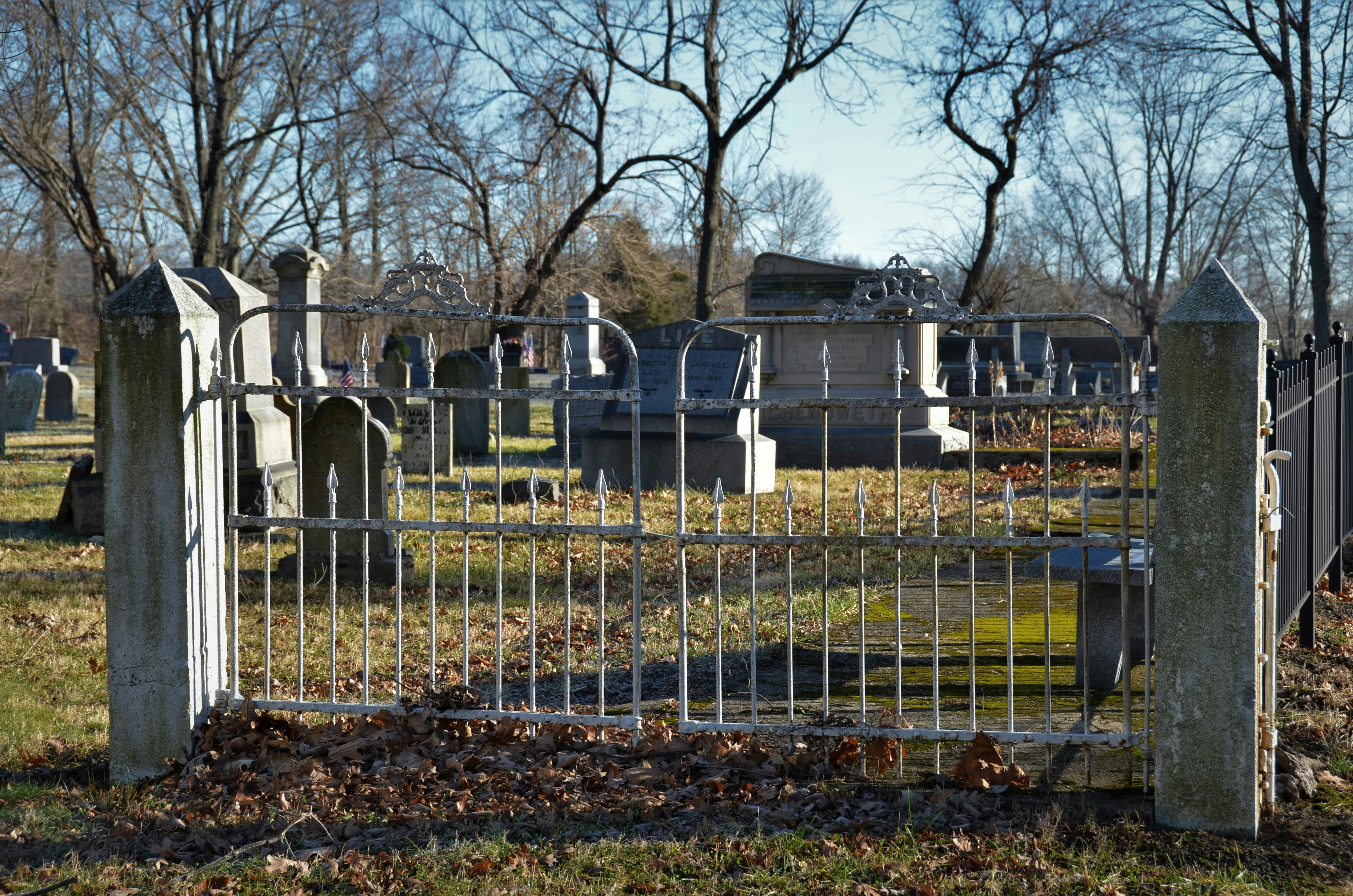 A cemetery with many headstones behind a fence photo – Free Building ...