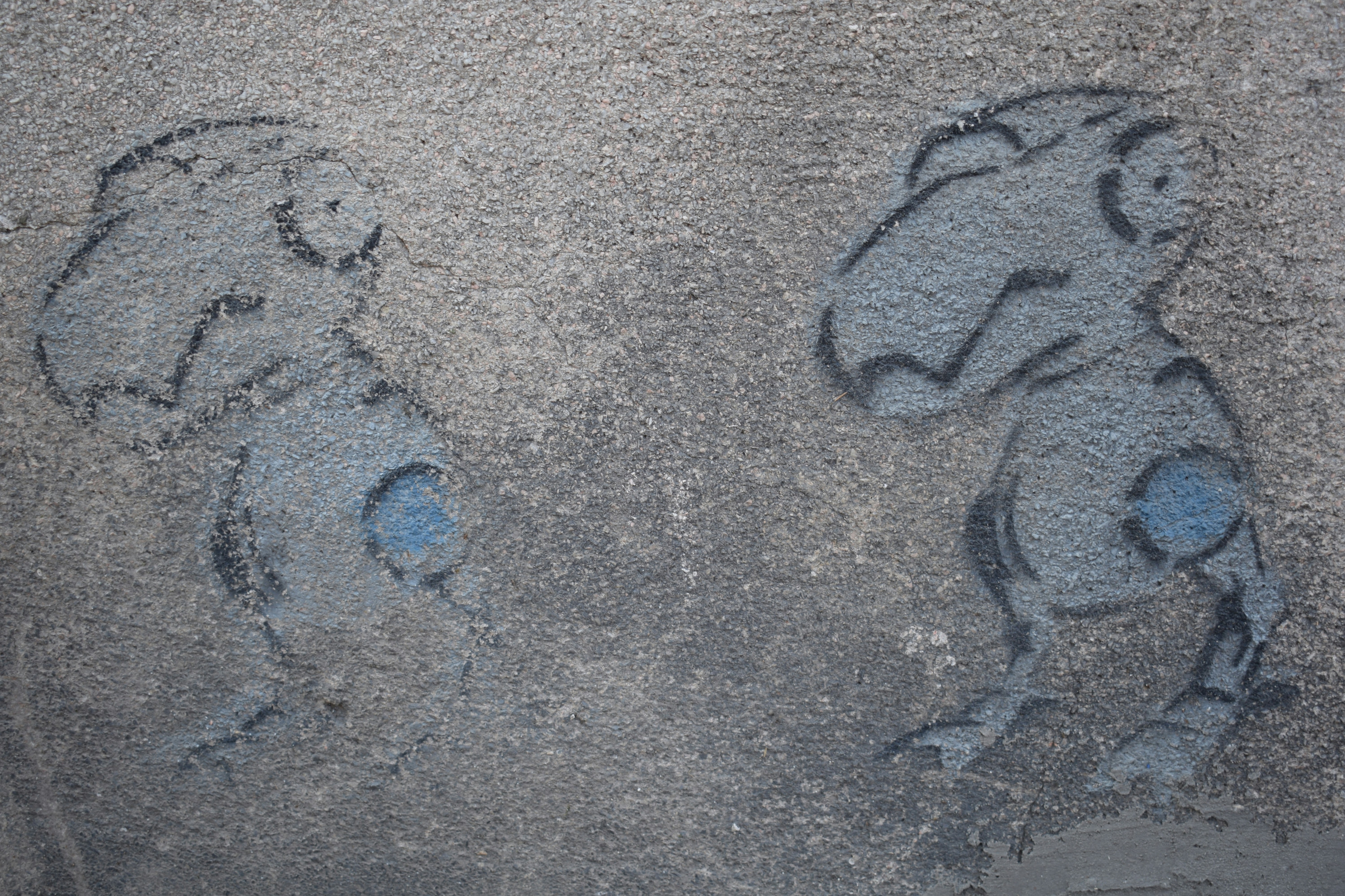 Two cartoonish robot figures spray-painted on a textured wall, showcasing a playful blend of technology and street art.