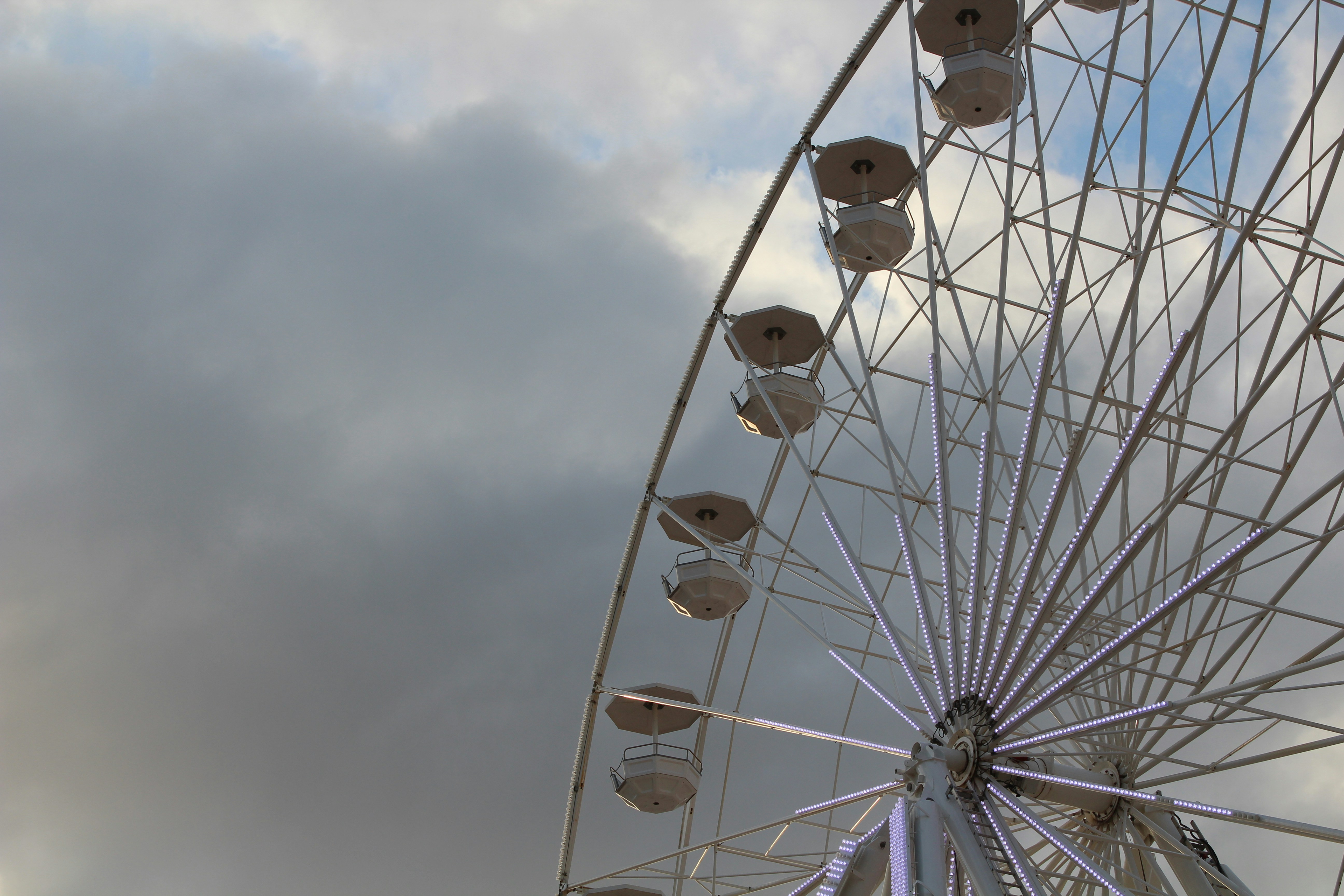 Ferris wheel adorned with lights against a backdrop of moody clouds, capturing the playful essence of amusement and wonder.