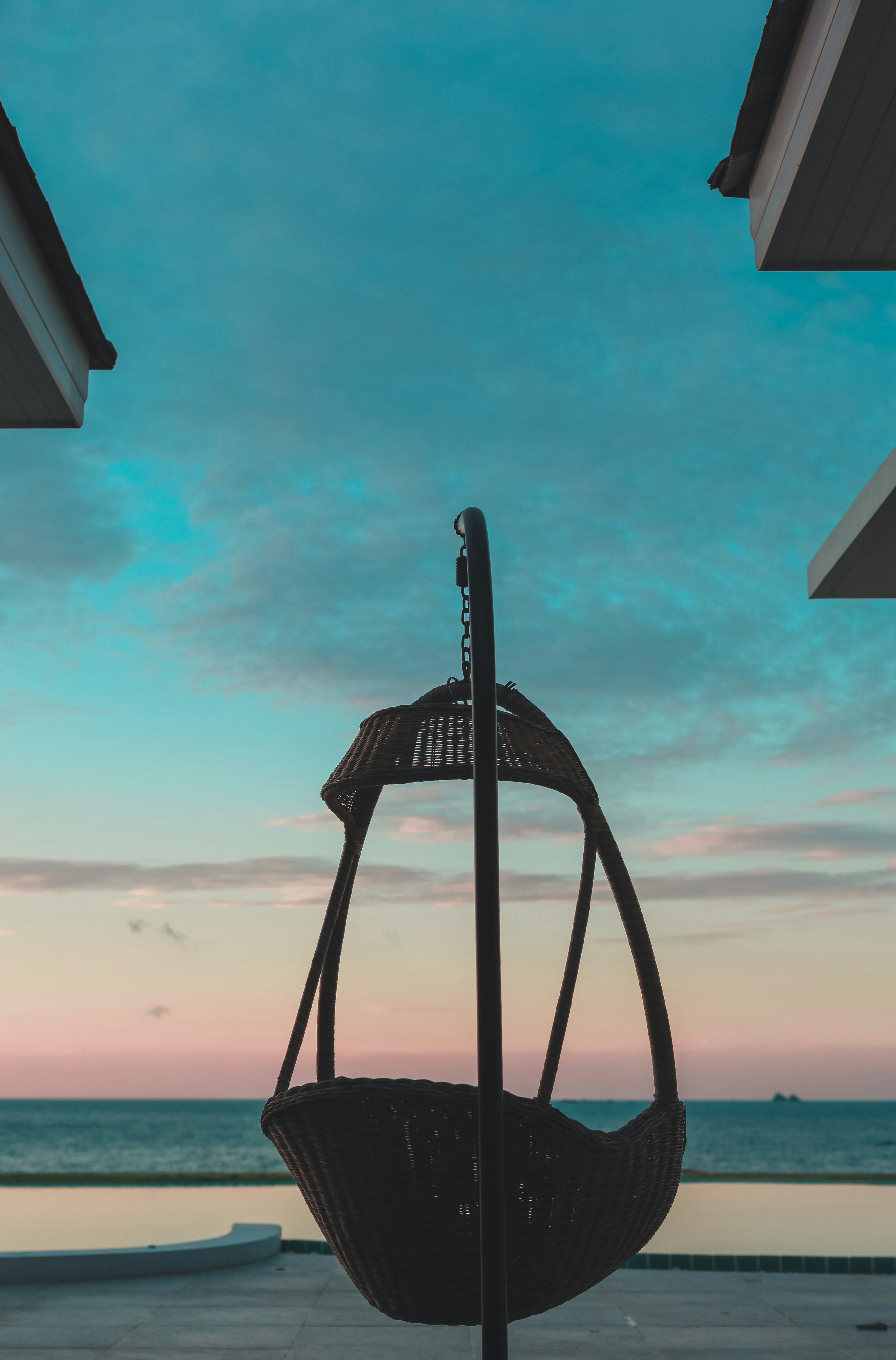 a swing sitting on top of a wooden floor next to the ocean