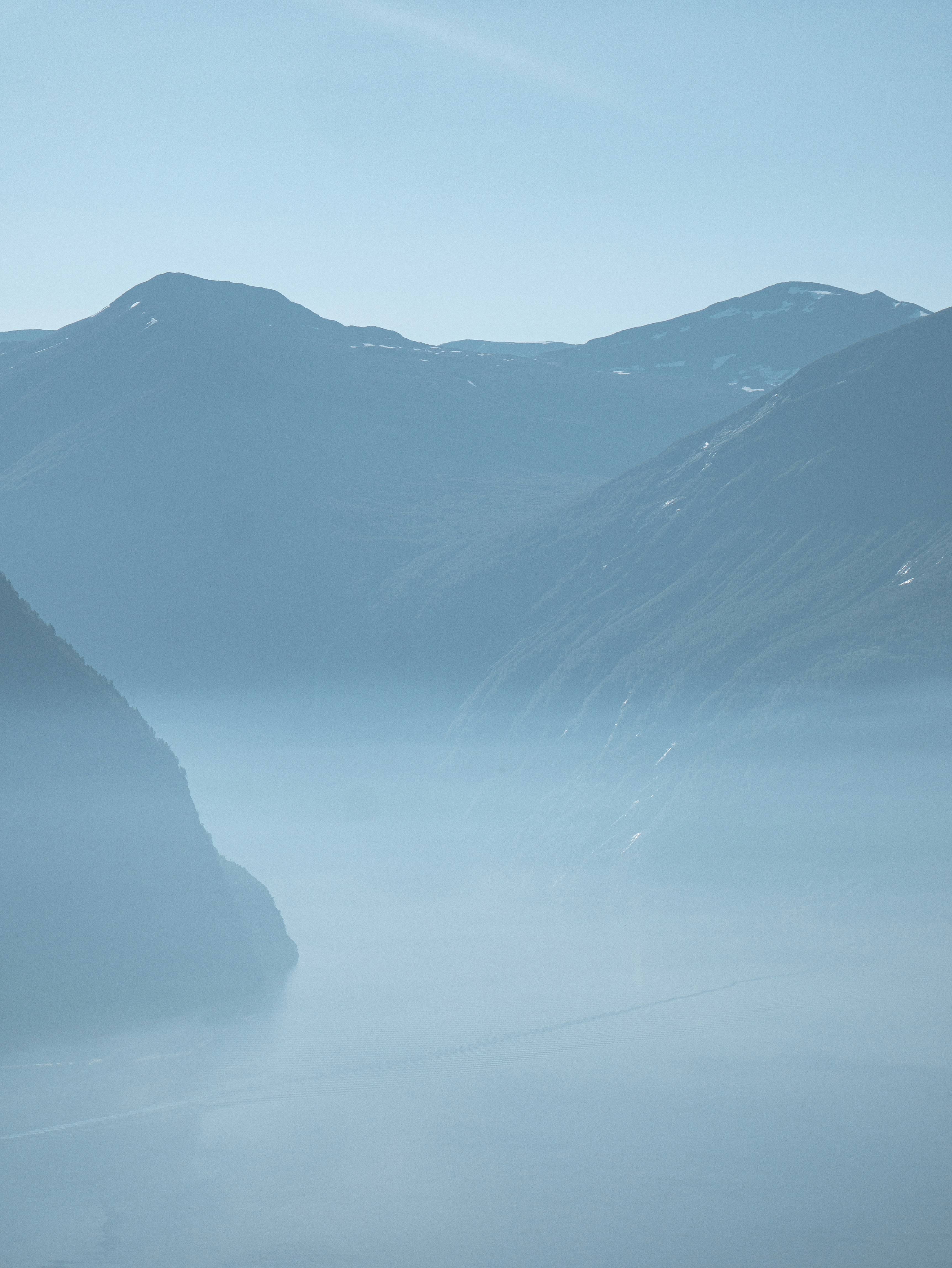 Misty landscape revealing layered mountains with soft blue hues and a tranquil atmosphere. Ideal for conveying the essence of nature's quiet beauty.