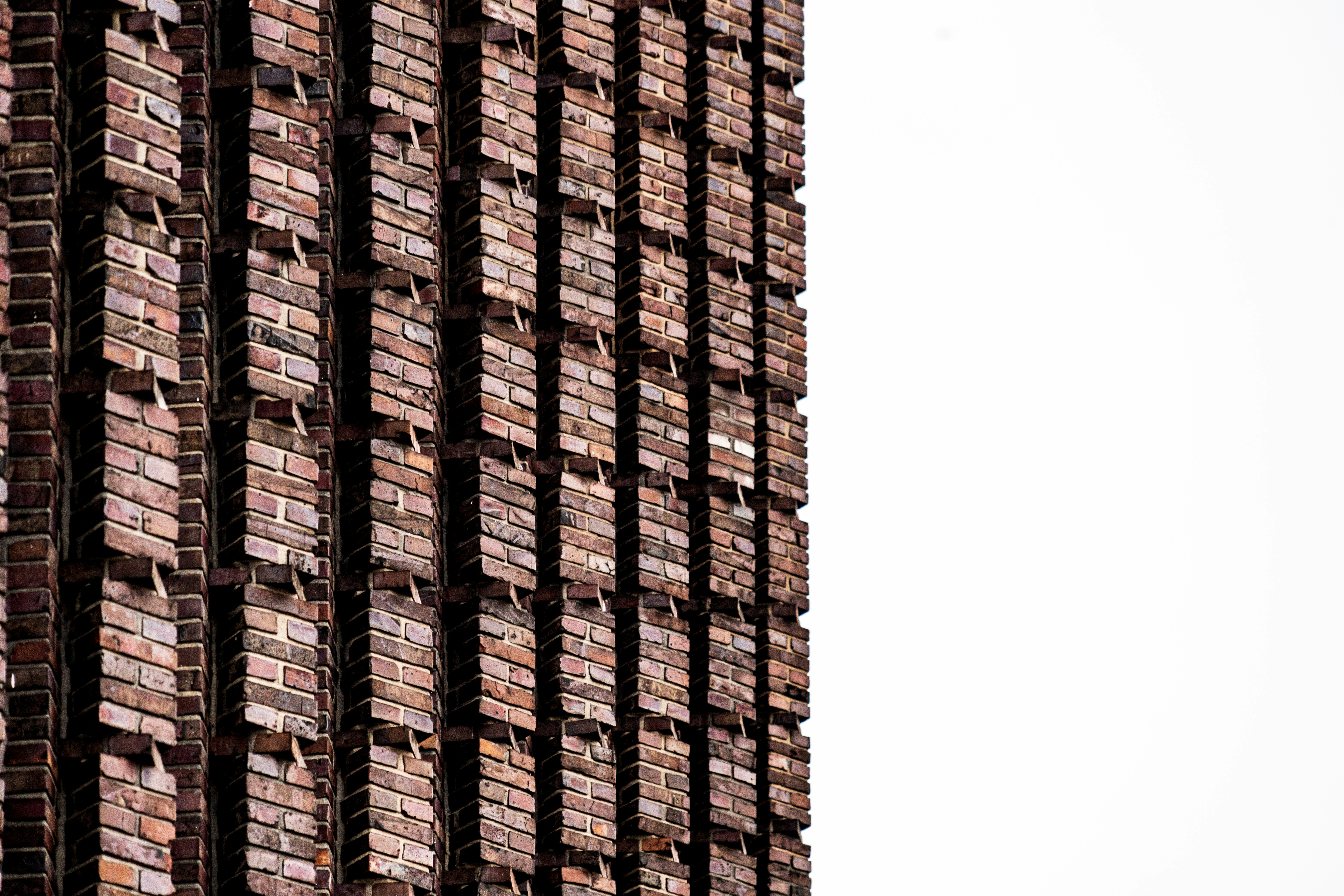 Detailed pattern of stacked bricks against a minimalistic white backdrop. The arrangement highlights the texture and structure of the material.