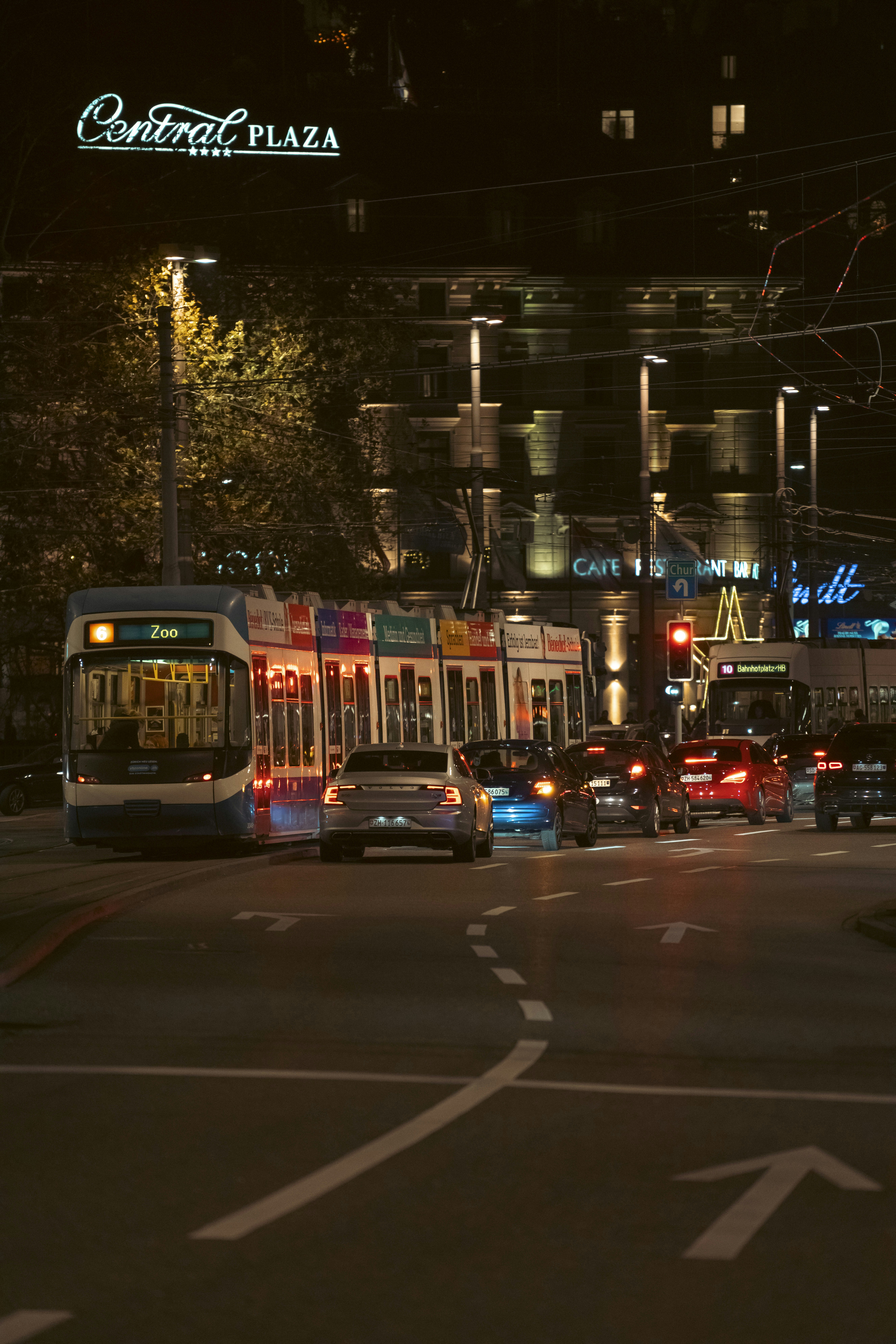 Neon Rails at Central Plaza: Night Tram Weaving Through City Traffic