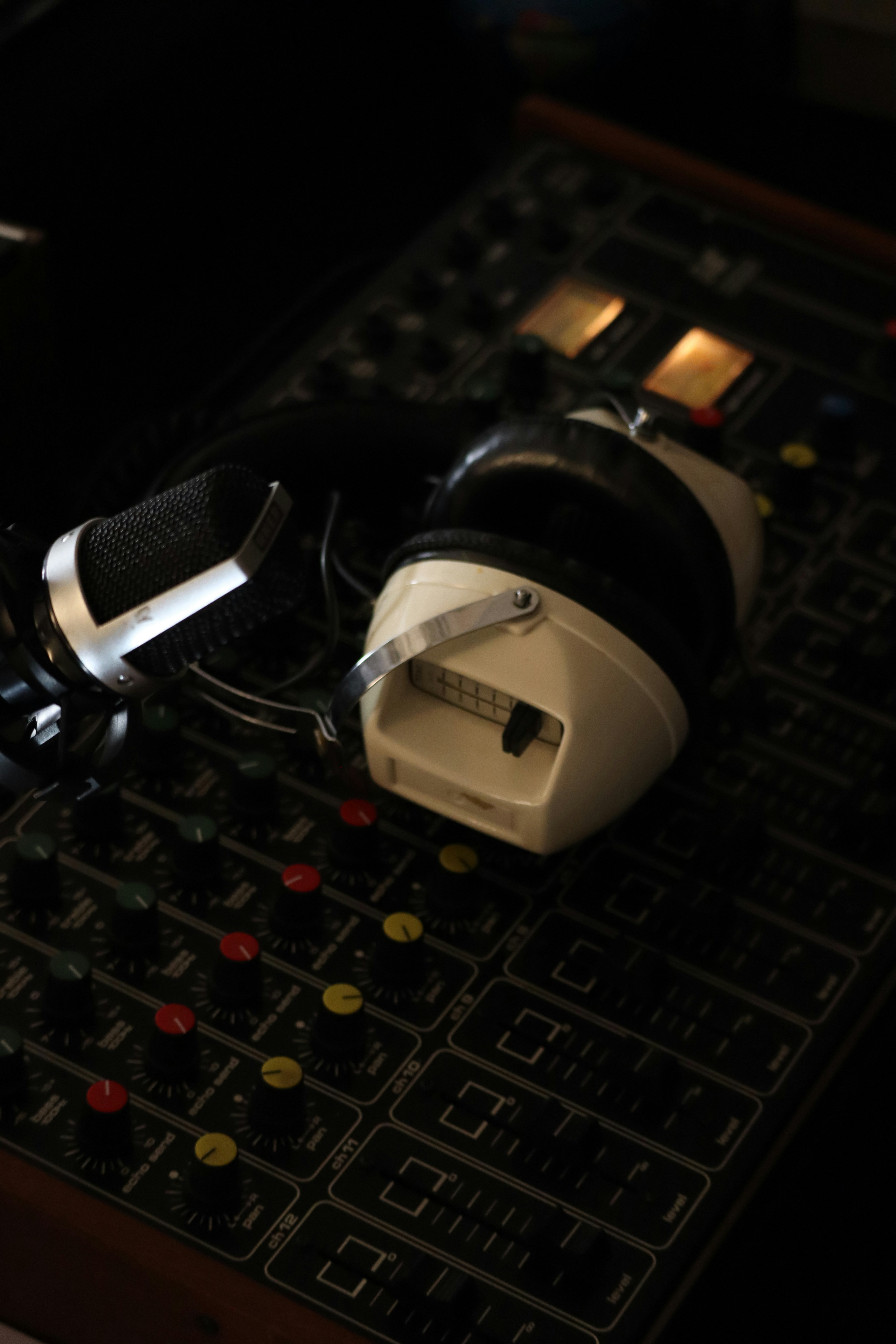Vintage microphone and headphones resting on a mixing console, showcasing the essence of audio production. 