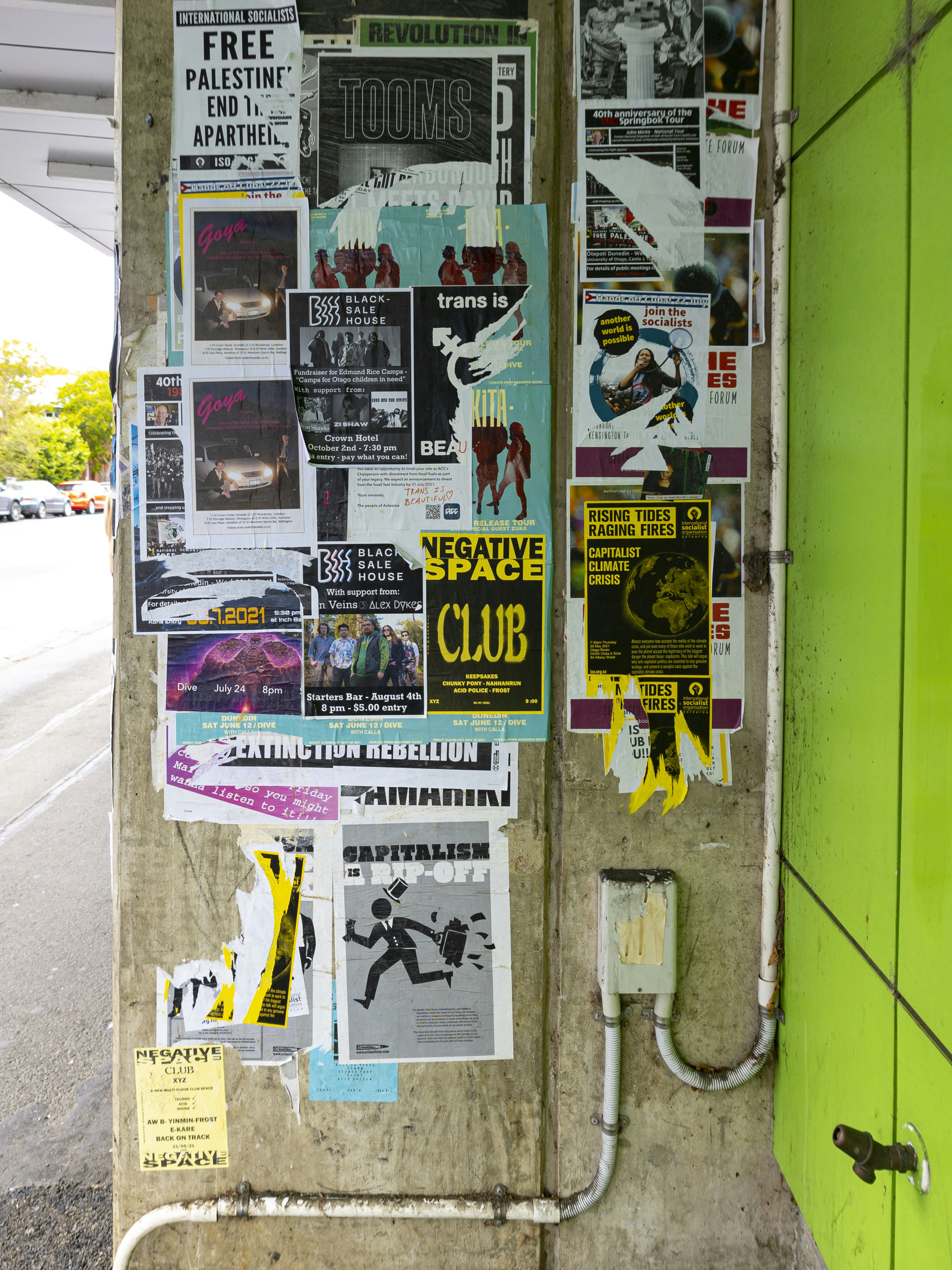 A collage of vibrant posters and flyers on a concrete wall, showcasing various social and political messages. The artwork reflects a dynamic urban culture.