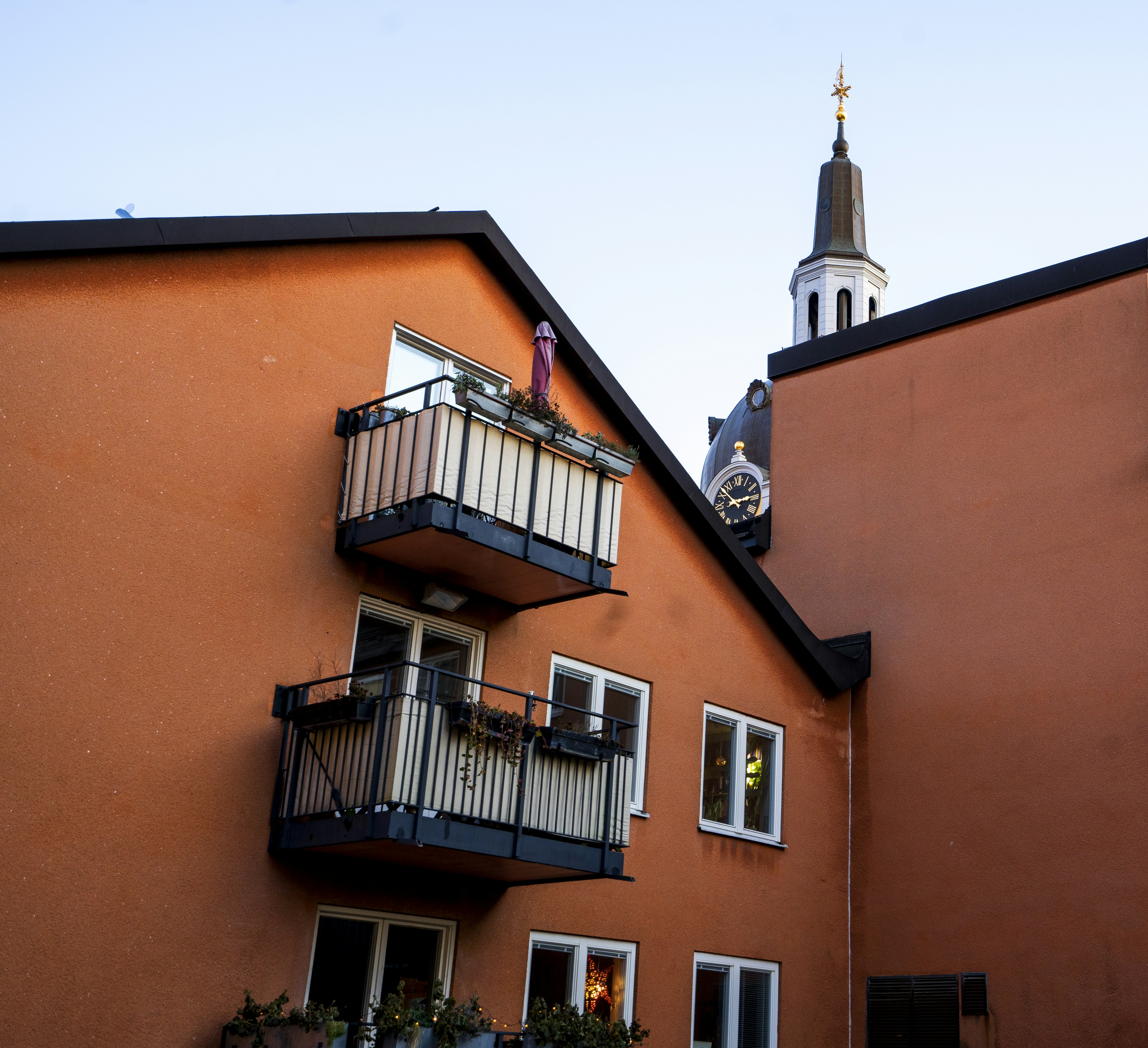 A tall orange building with a clock tower in the background photo ...