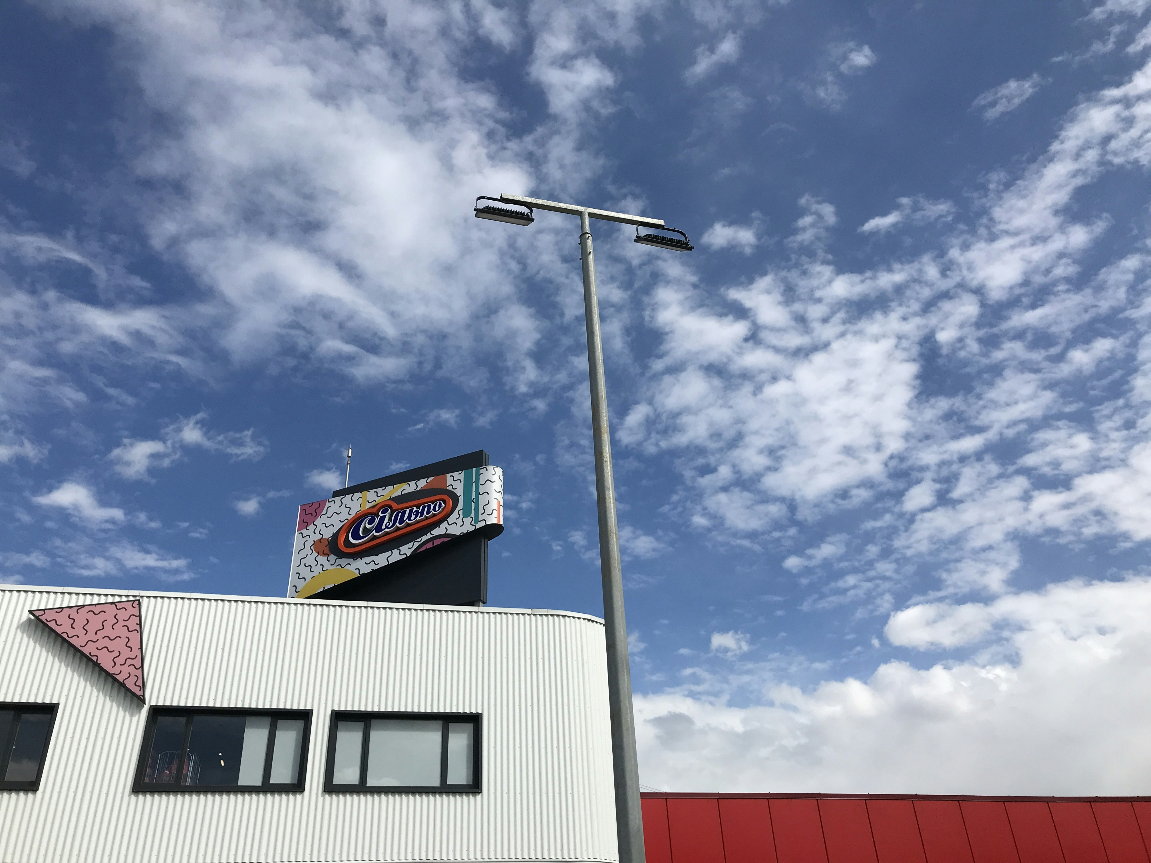 Lone Streetlight Framing a Billboard Under a Wide Blue Sky