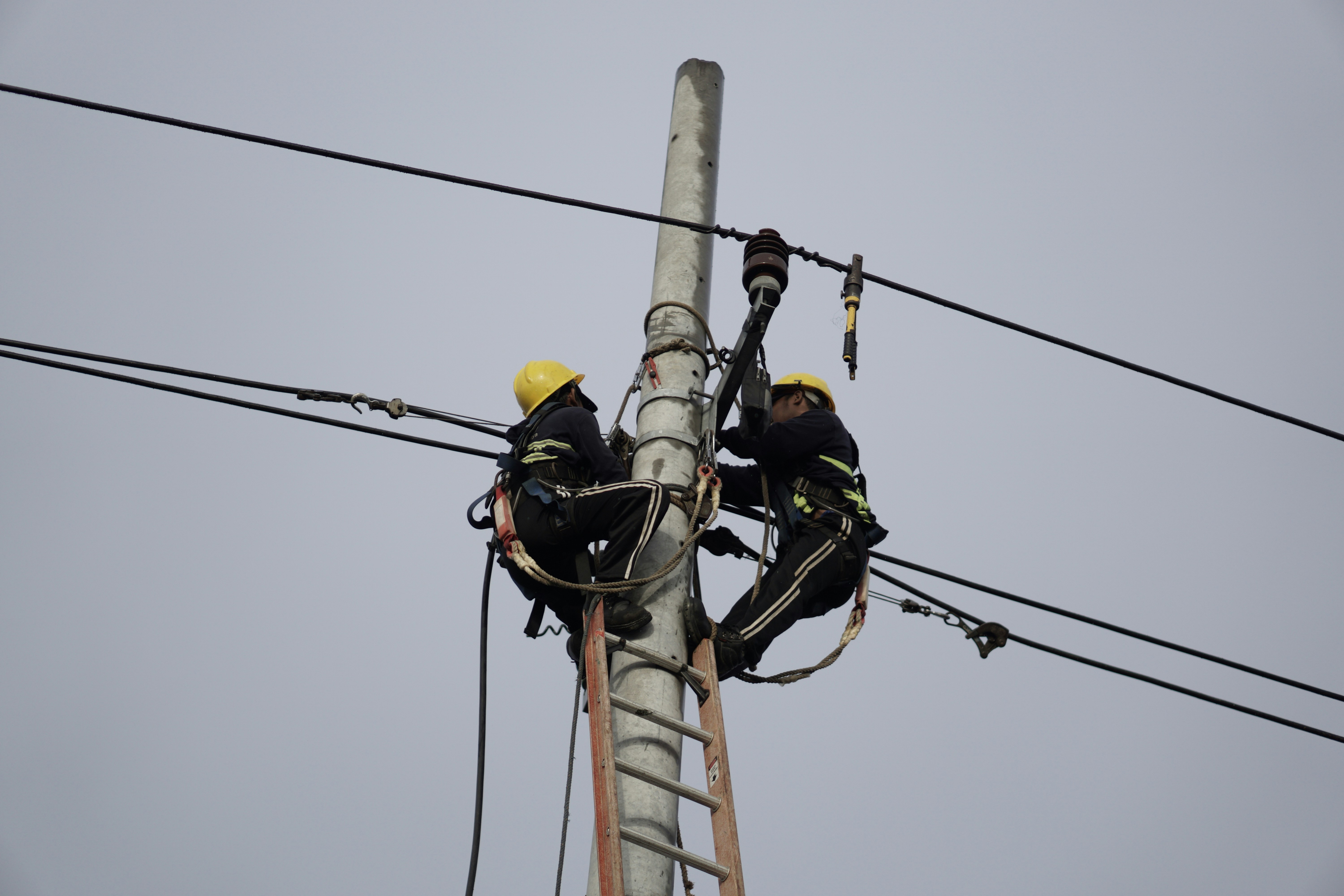 A couple of men standing on top of power lines photo – Free Denpasar ...