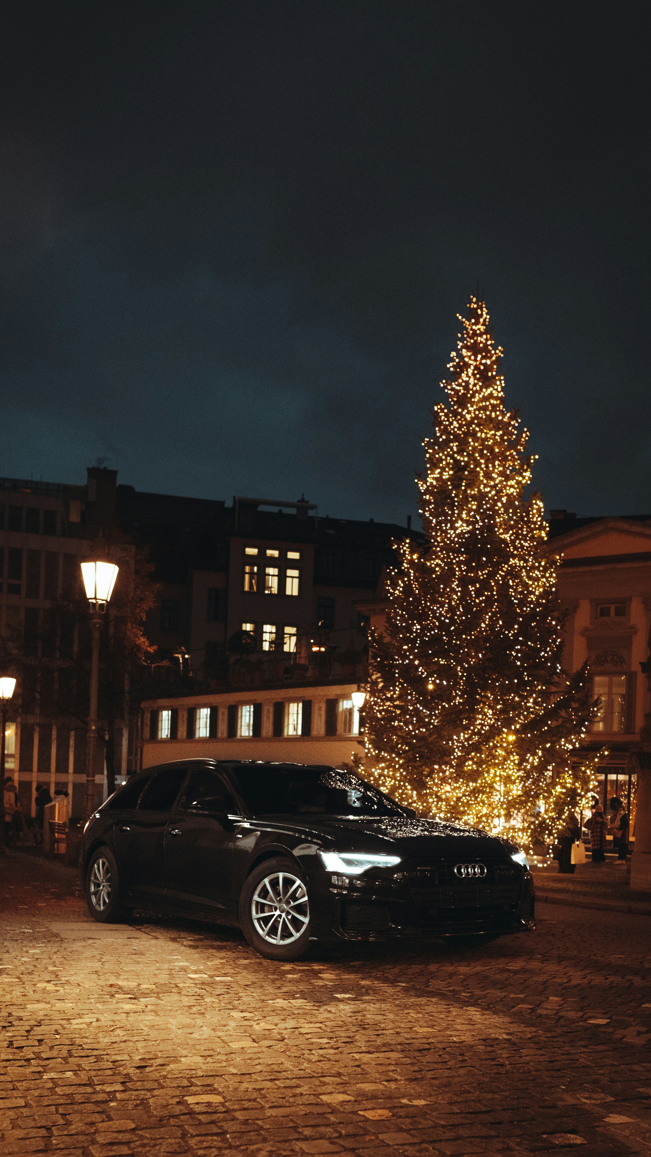 Nighttime Glory: A Black Audi Anchored by a Glowing Christmas Tree