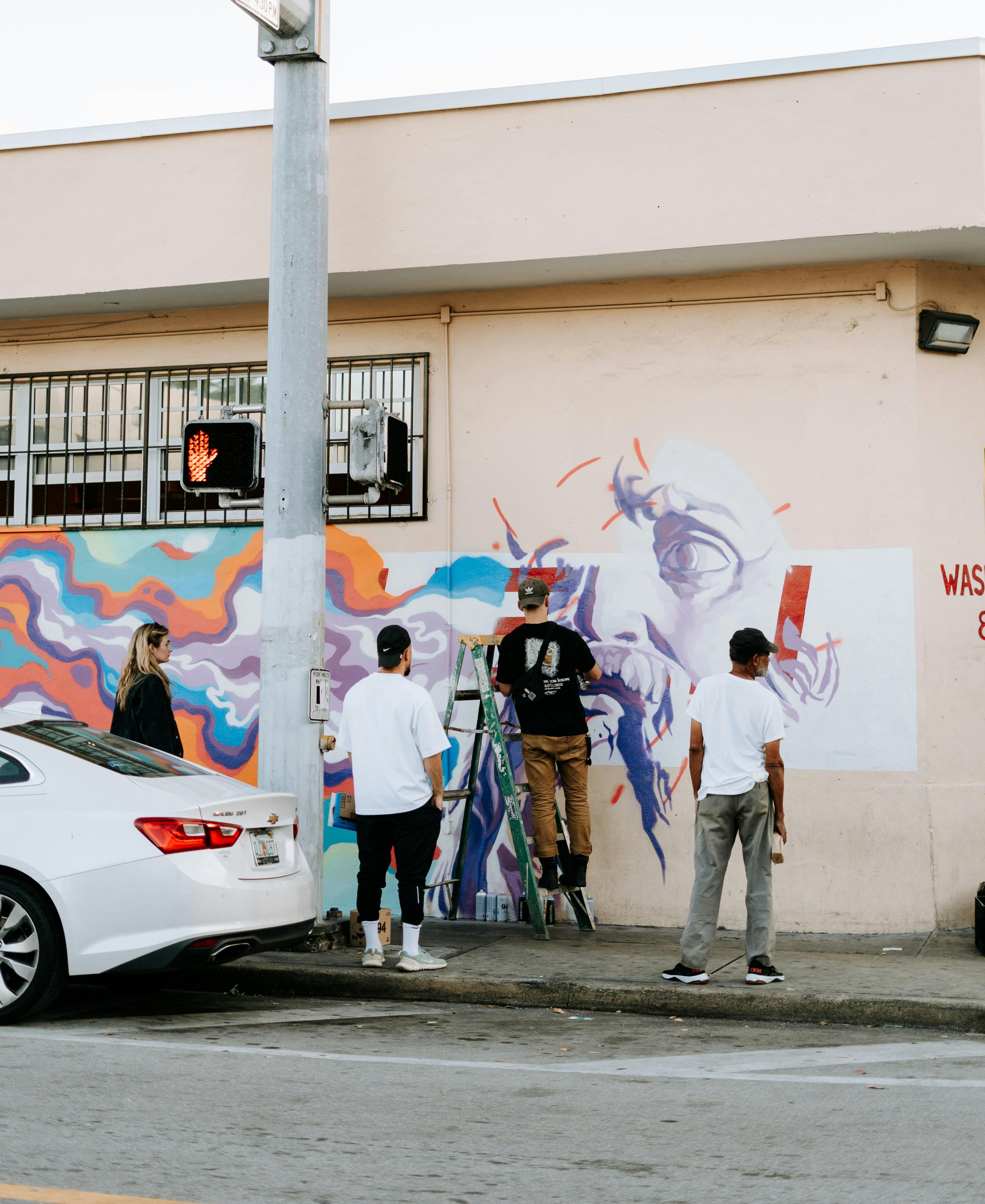 A group of people painting a mural on the side of a building photo ...