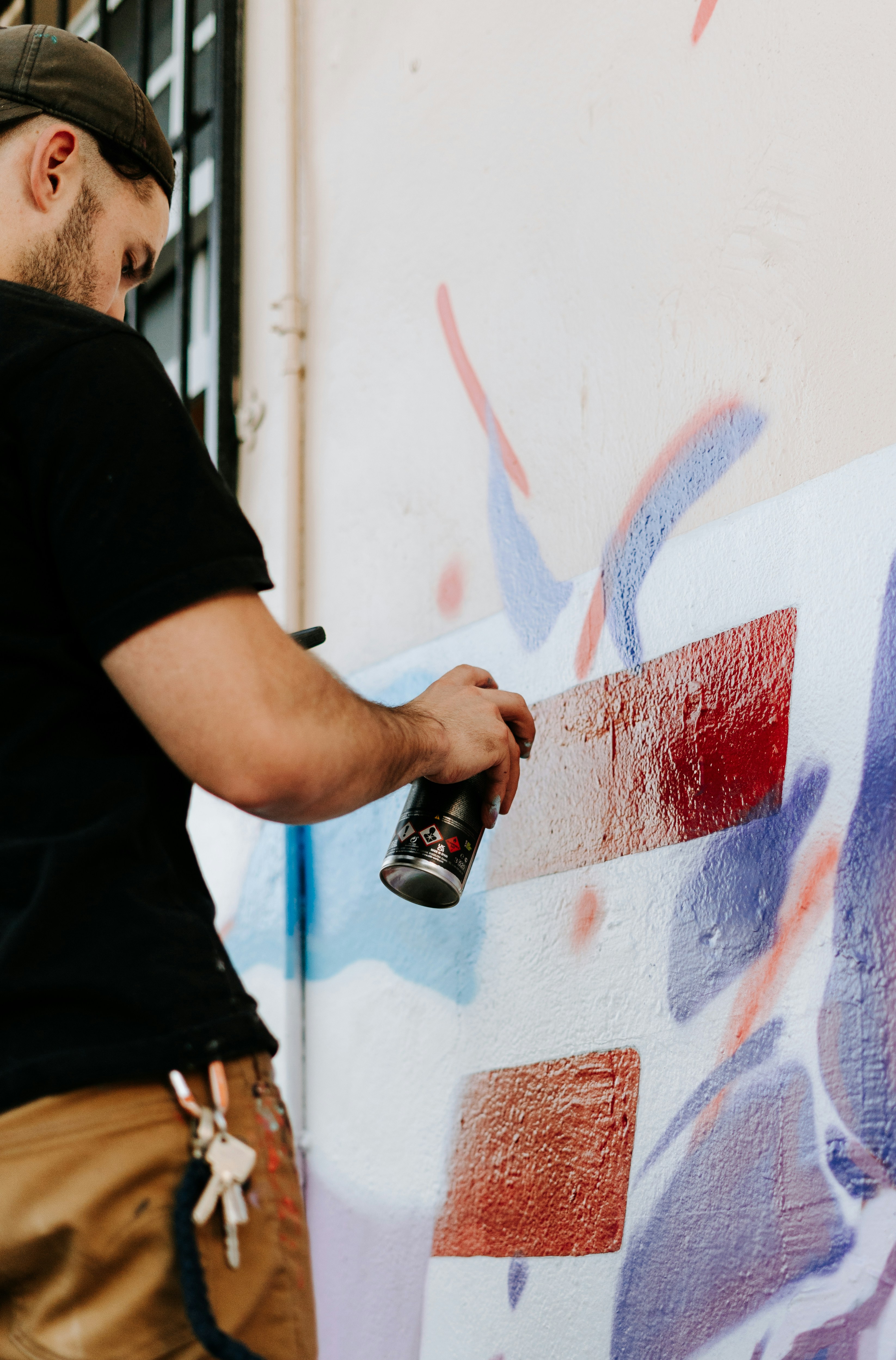 A man spray painting a wall with graffiti photo – Free Wxllspace Image ...