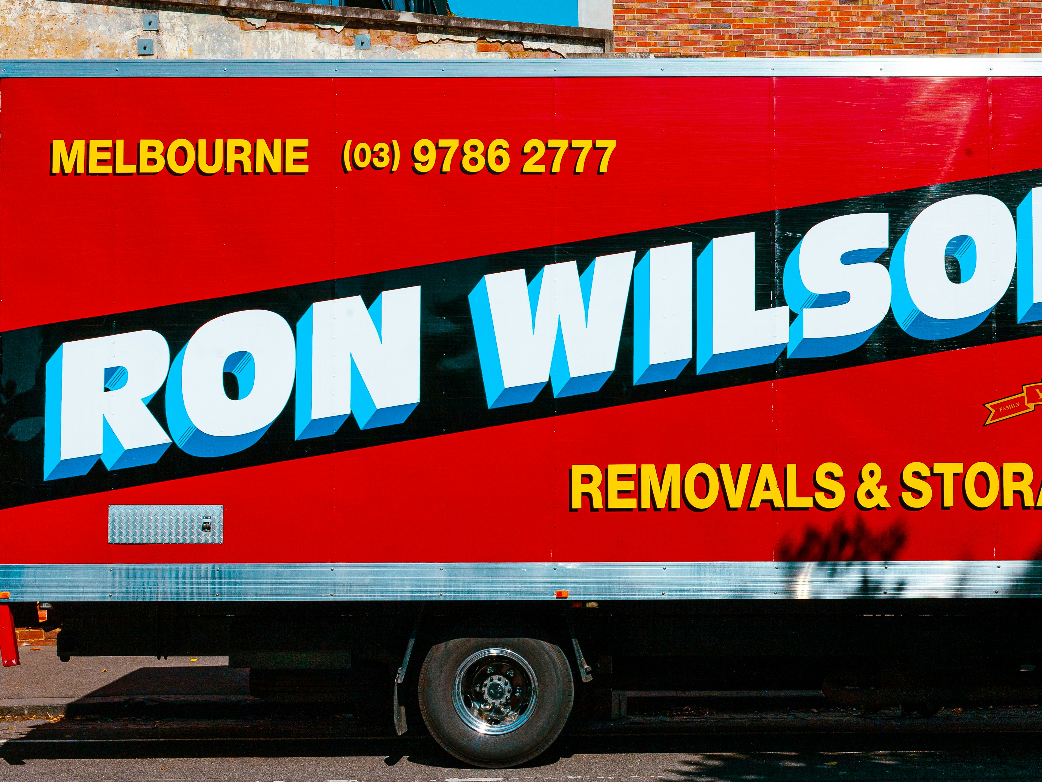 A red box truck parked in front of a brick building photo – Free ...