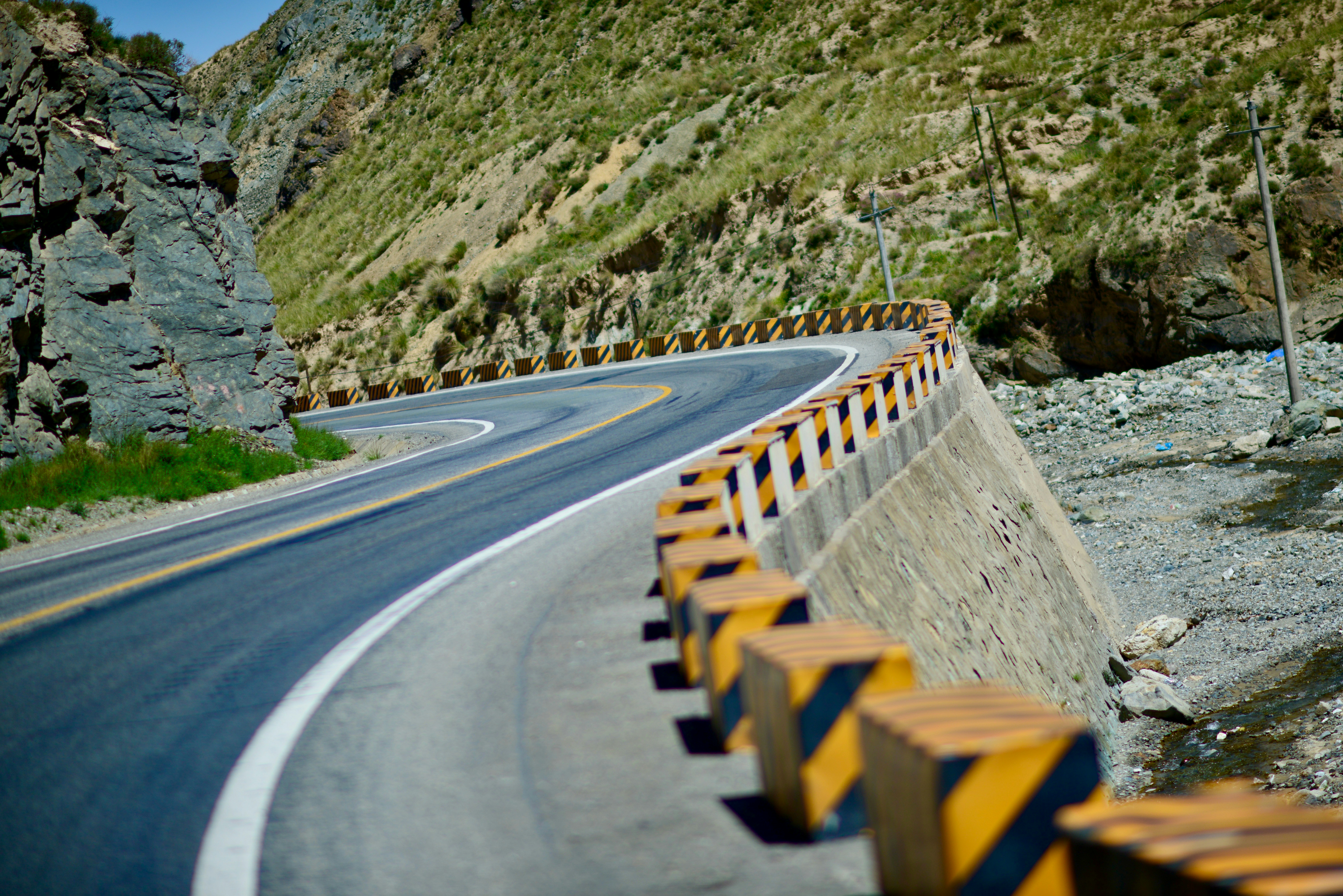 Curved Cliff Pass: A Winding Mountain Road Between Striped Barriers