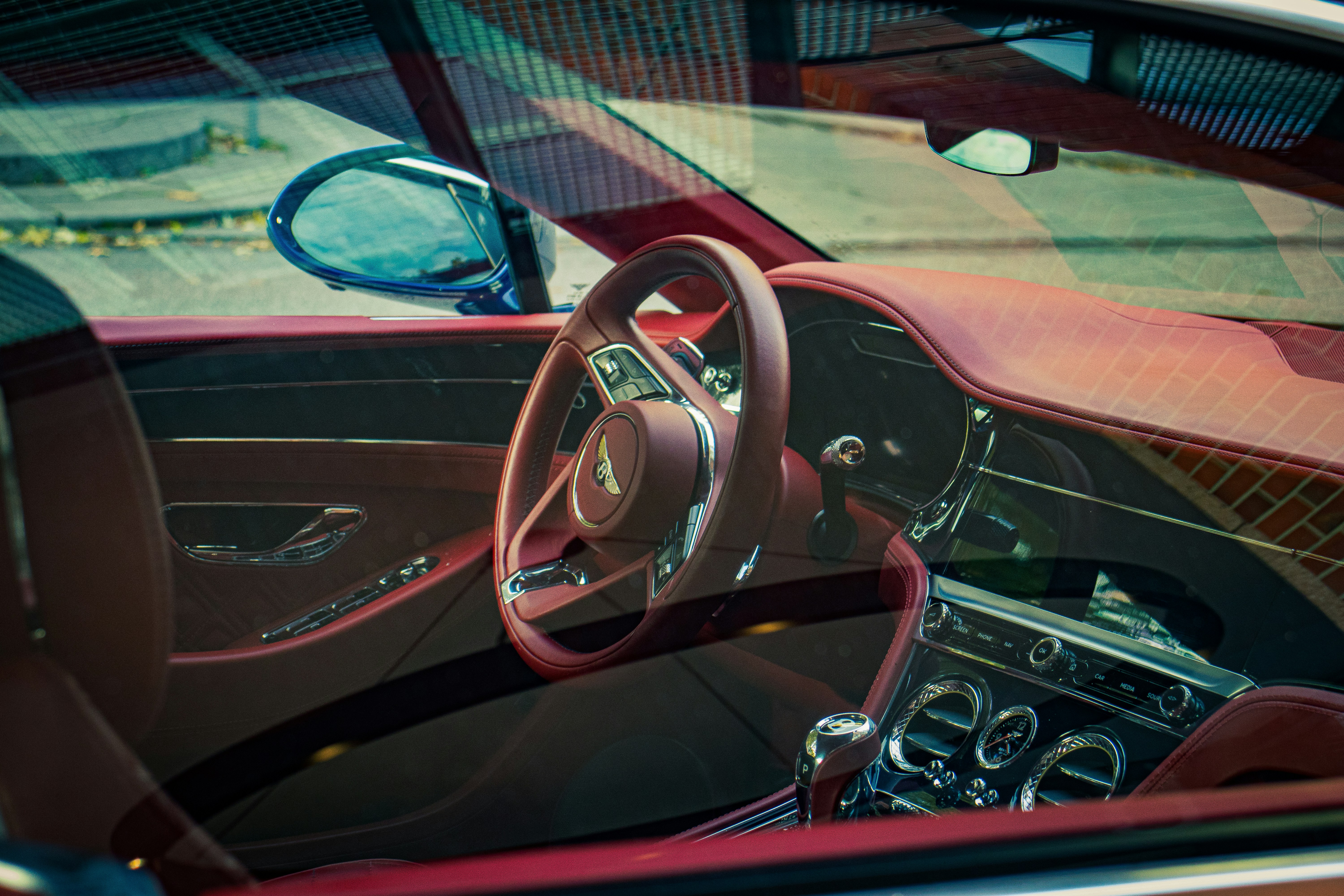 Interior of a luxury car featuring rich red leather and polished details, showcasing a blend of comfort and sophistication.