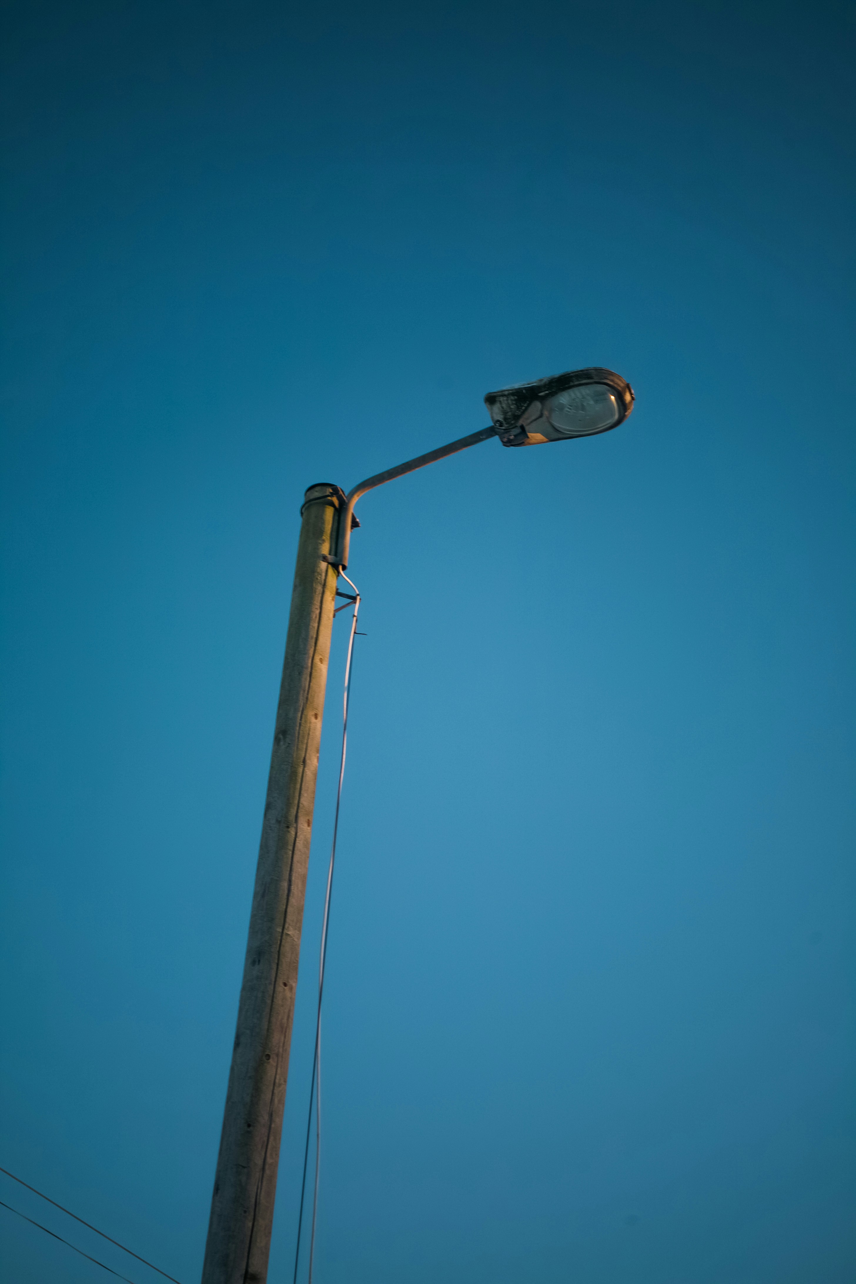 A solitary streetlight stands tall against a clear blue sky, casting a sense of vigilance over the urban landscape.