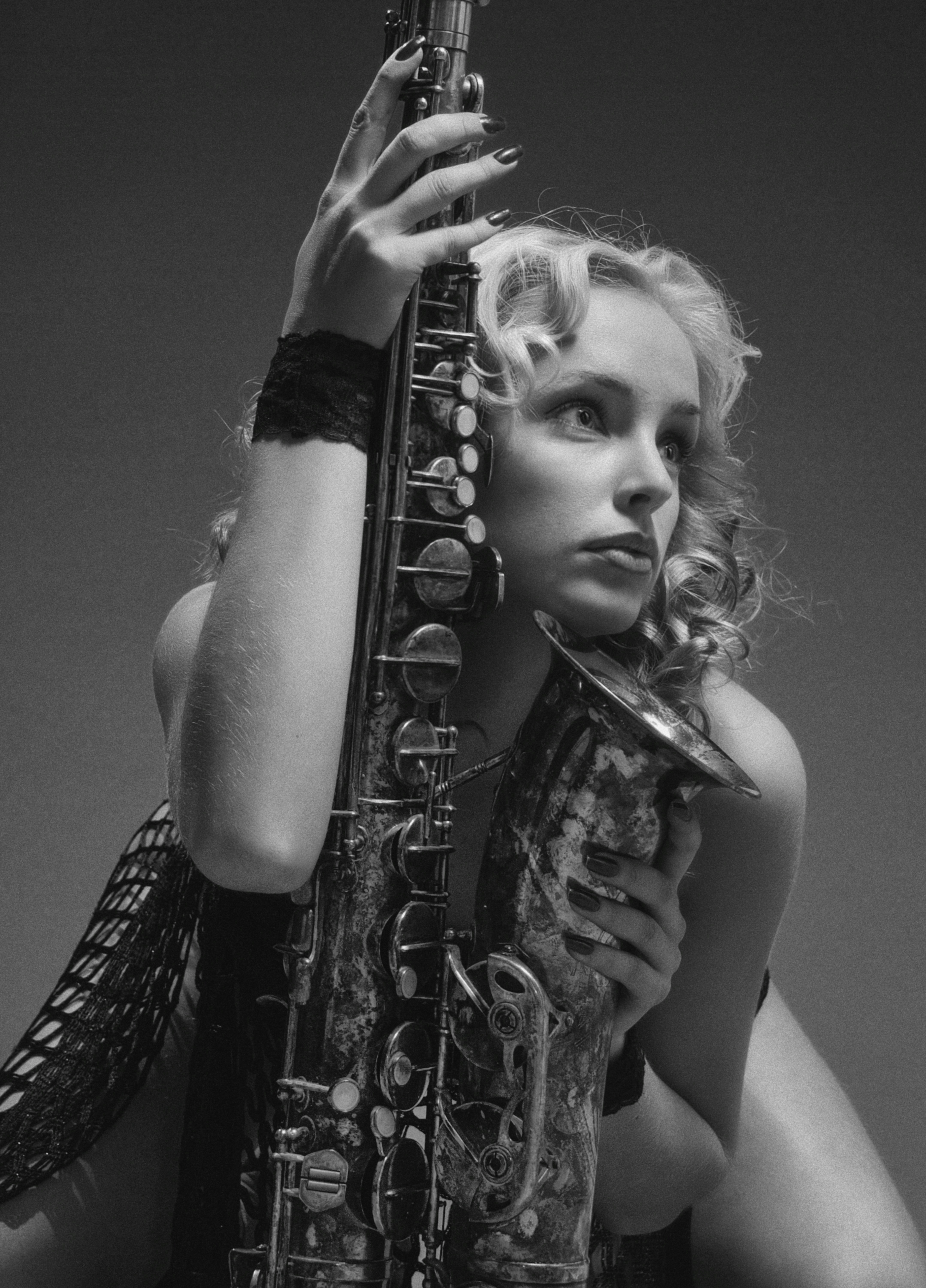 A woman holding a saxophone up to her face photo – Free Grey Image on ...