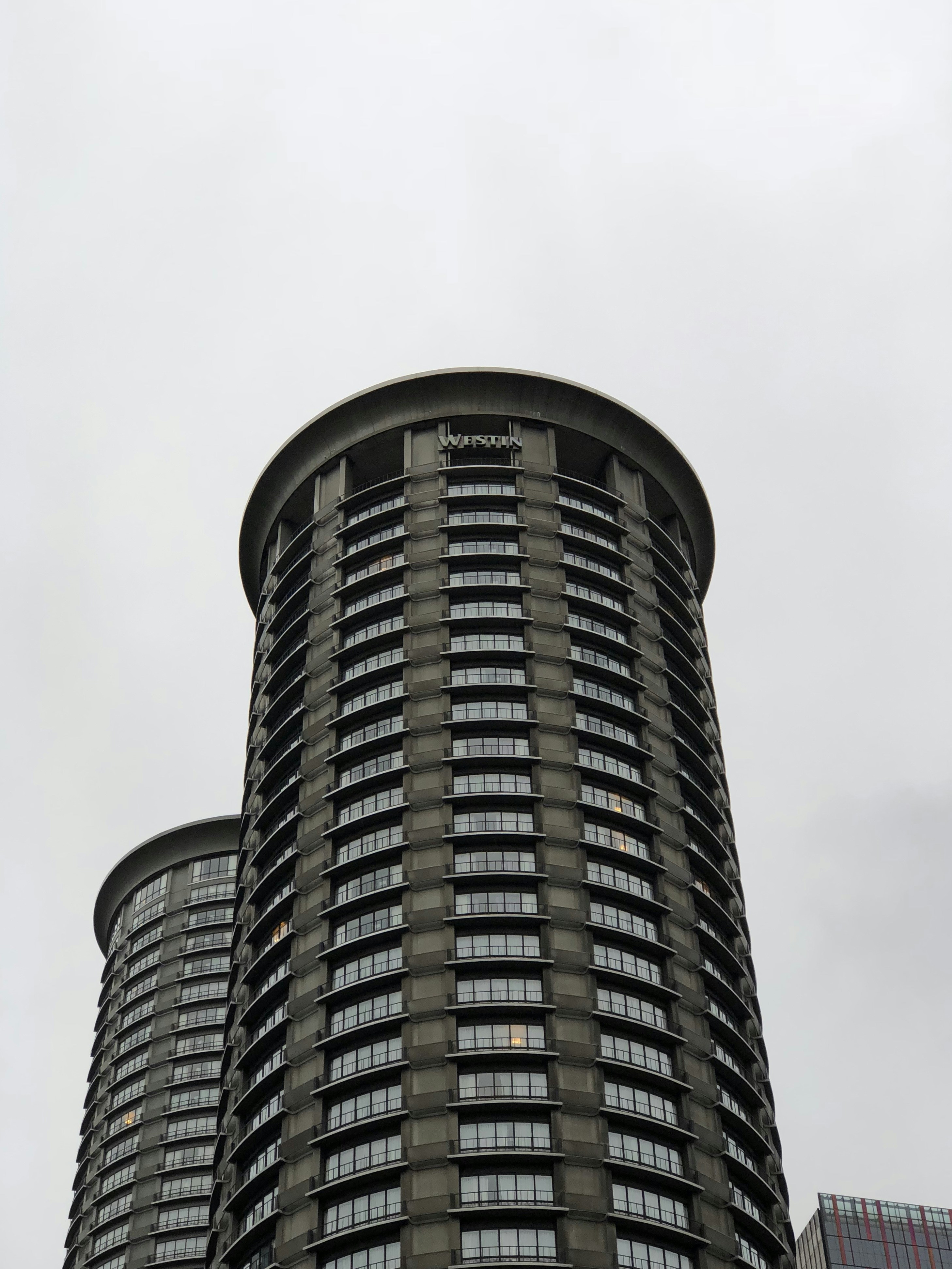 Modern high-rise buildings with rounded tops rise against a cloudy sky, showcasing architectural design and urban living.
