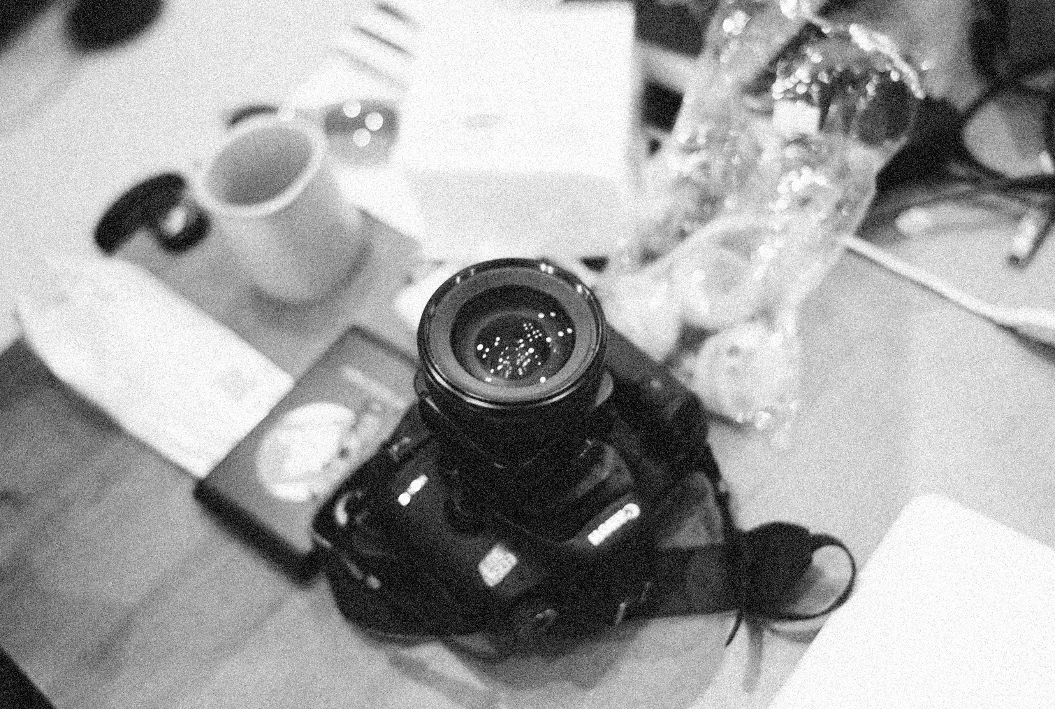 Camera resting on a cluttered table surrounded by everyday objects and tools of creativity.